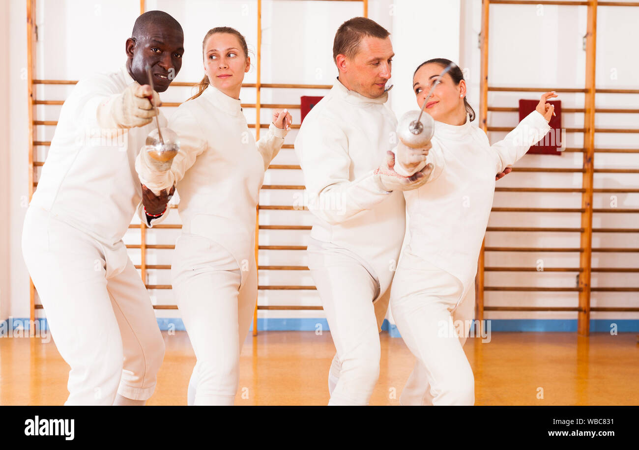 Emotional men and women fencers posing with foils together at fencing ...