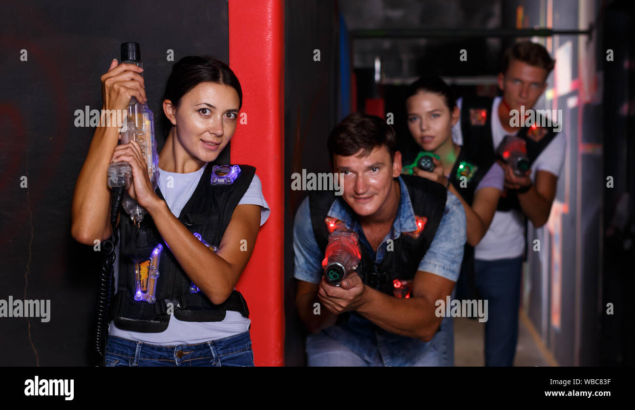 Group smiling emotional people with laser guns playing laser tag game ...