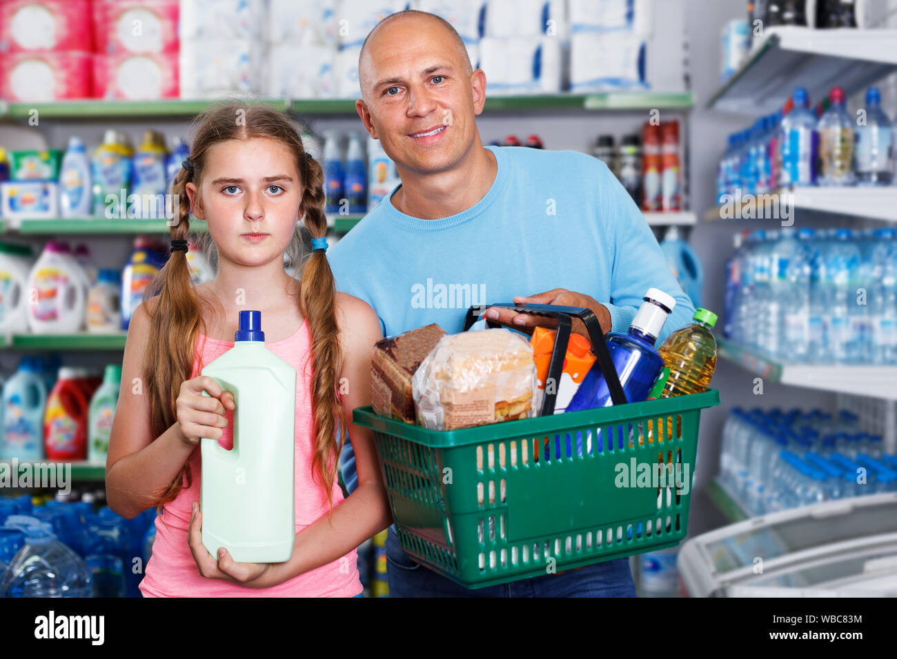 Portrait of positive man with tween daughter choosing household ...