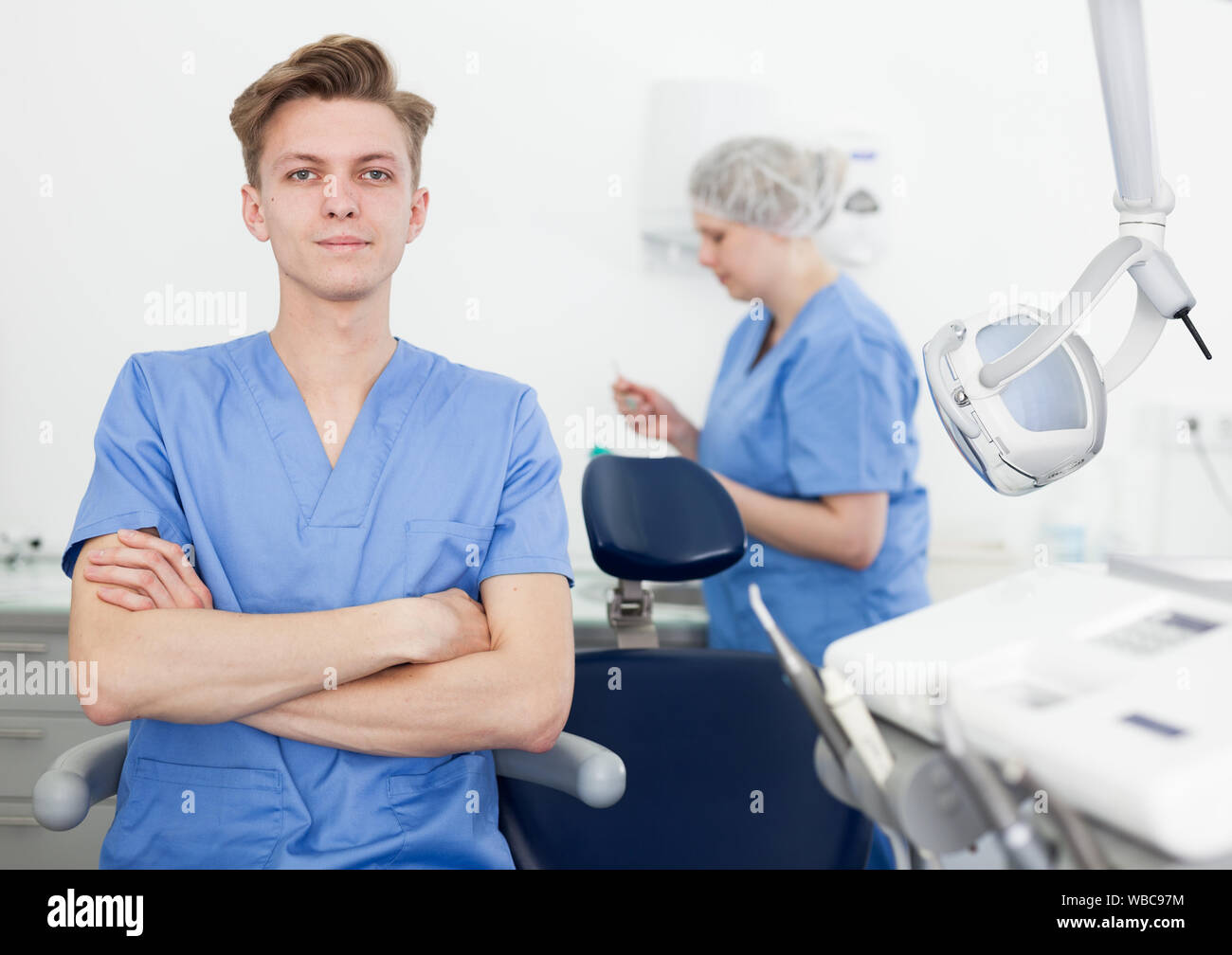 Portrait of professional male dentist with arms crossed with dental ...