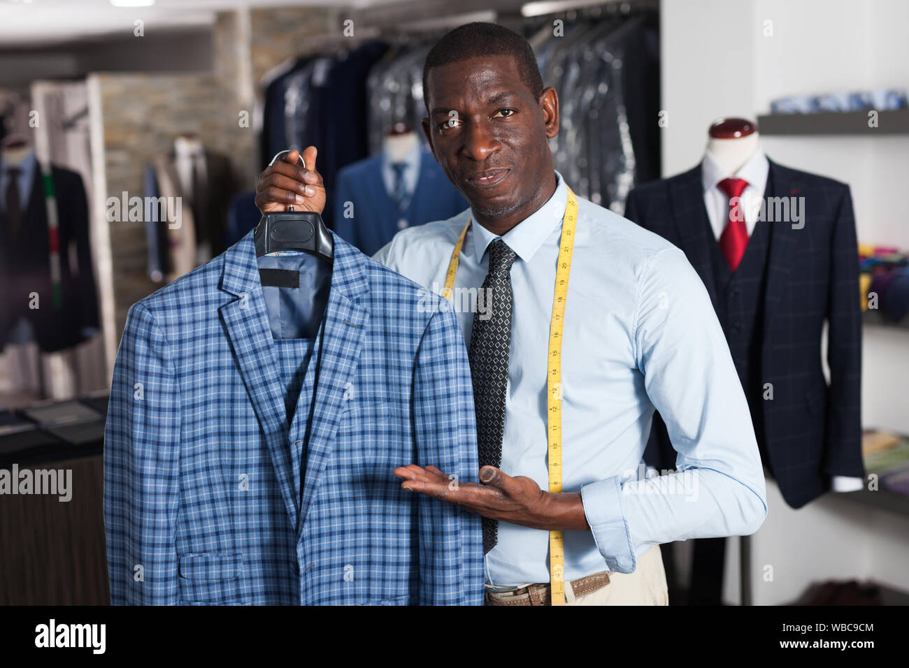 Male tailor demonstrating of fashionable suit in apparel shop Stock ...