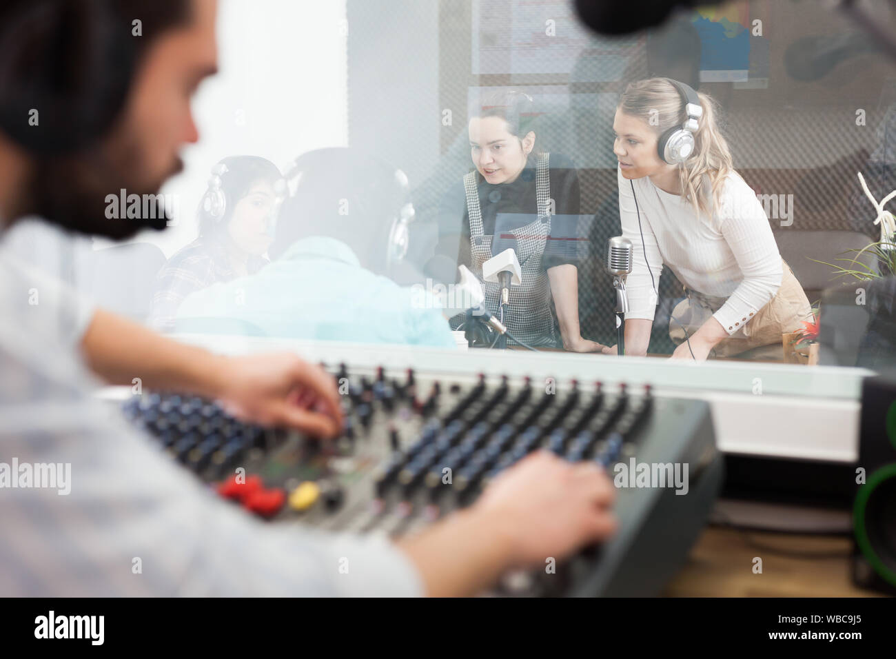 Group of glad young adults emotionally discussing in radio studio. View ...
