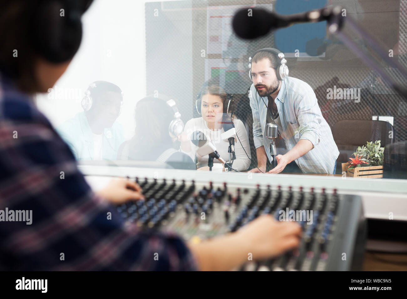 Young presenters in sound broadcasting station hosting live radio show ...