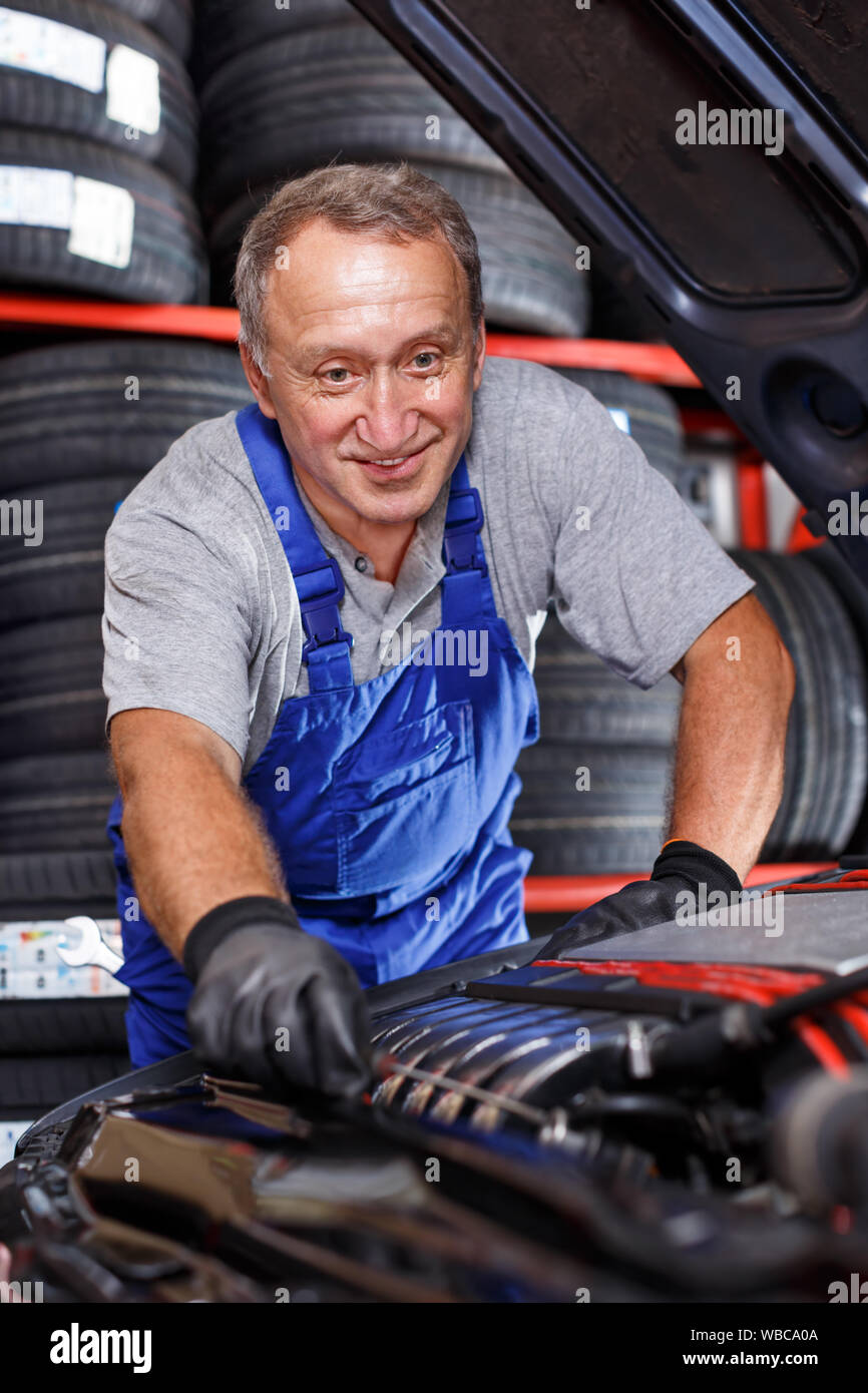 Skilled mechanic technician working at a service station, repairing a ...