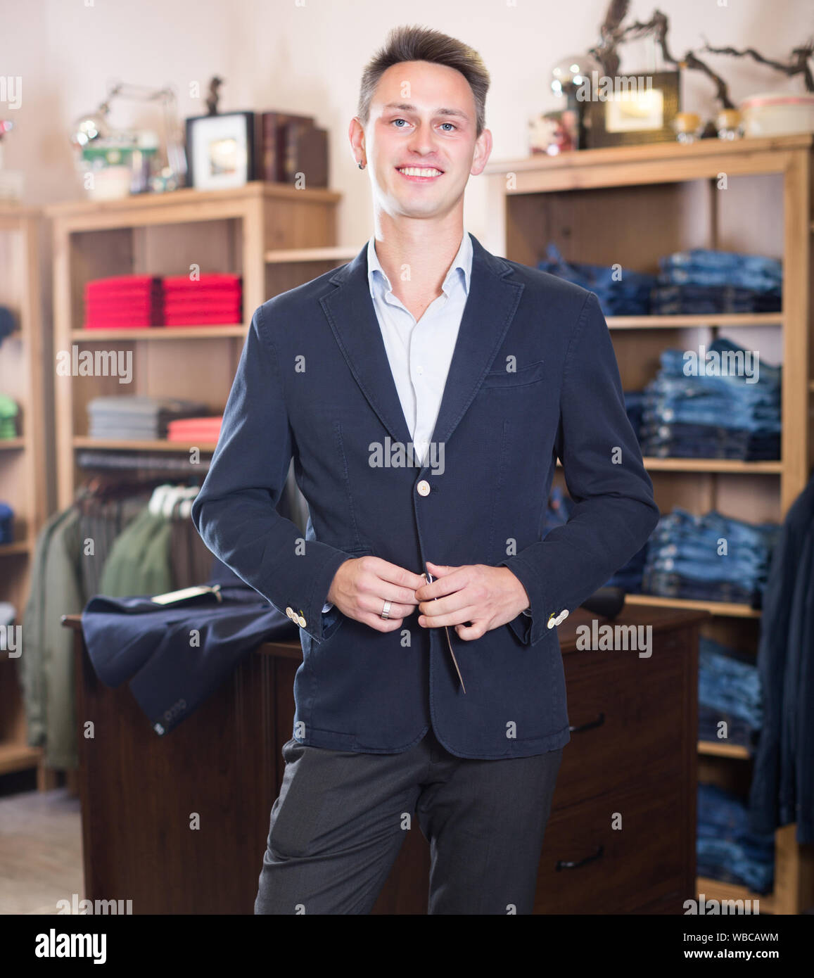 Adult male is trying on new dark blue jacket in men's clothes store ...