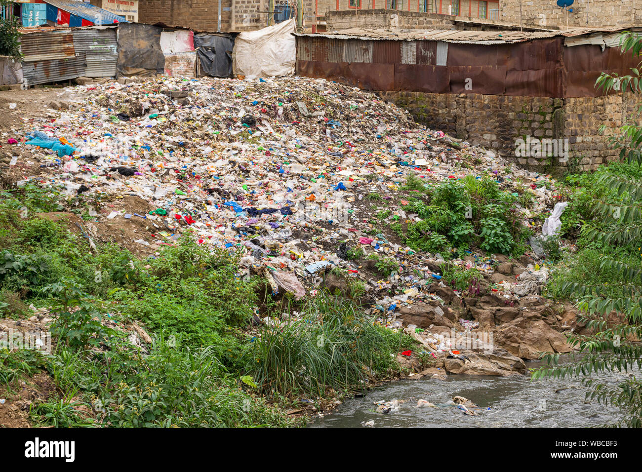 Mathare river with large pile of rubbish on the ground next to it ...