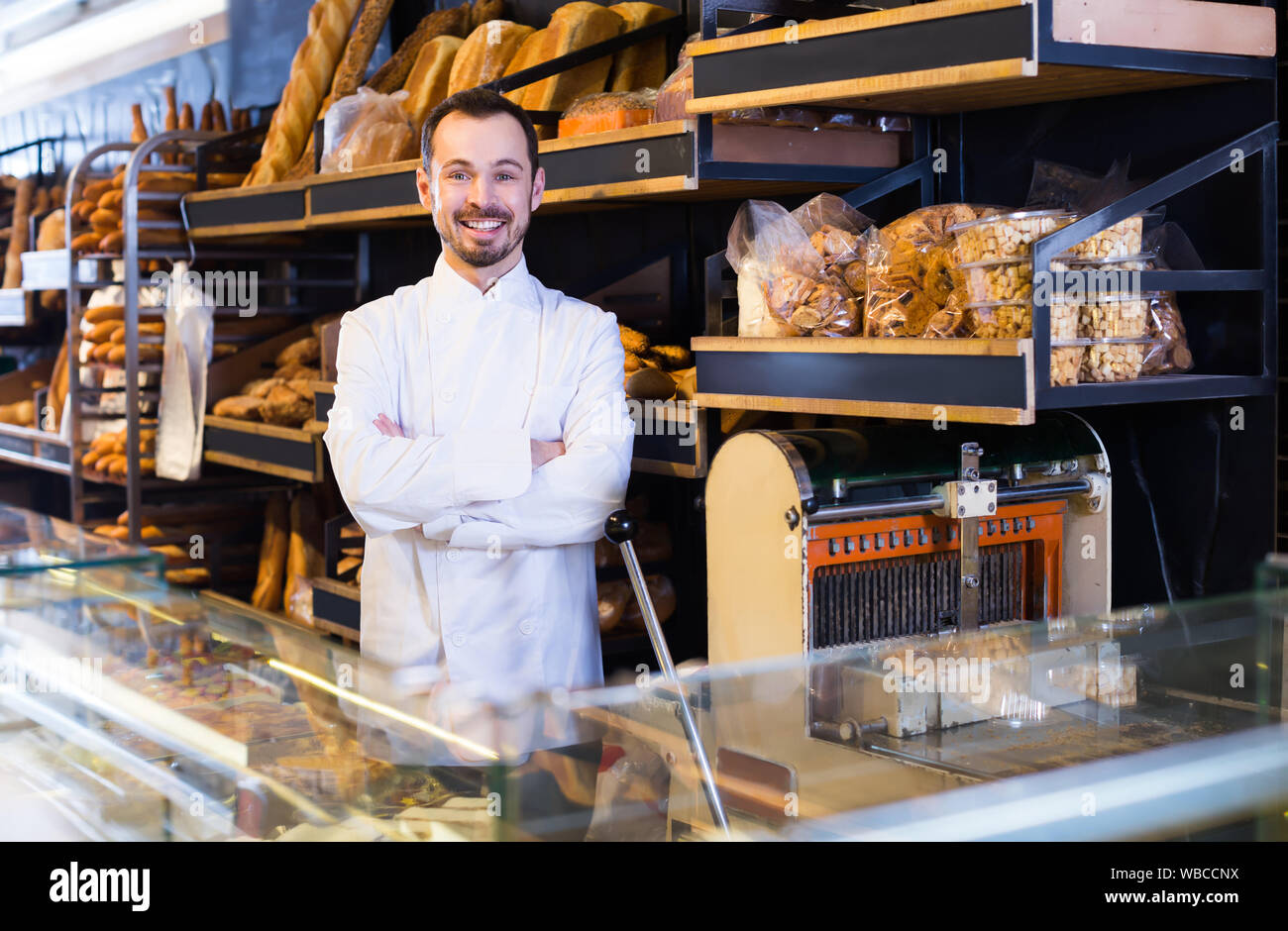 Positive male pastry maker demonstrating pastry in bakery Stock Photo ...