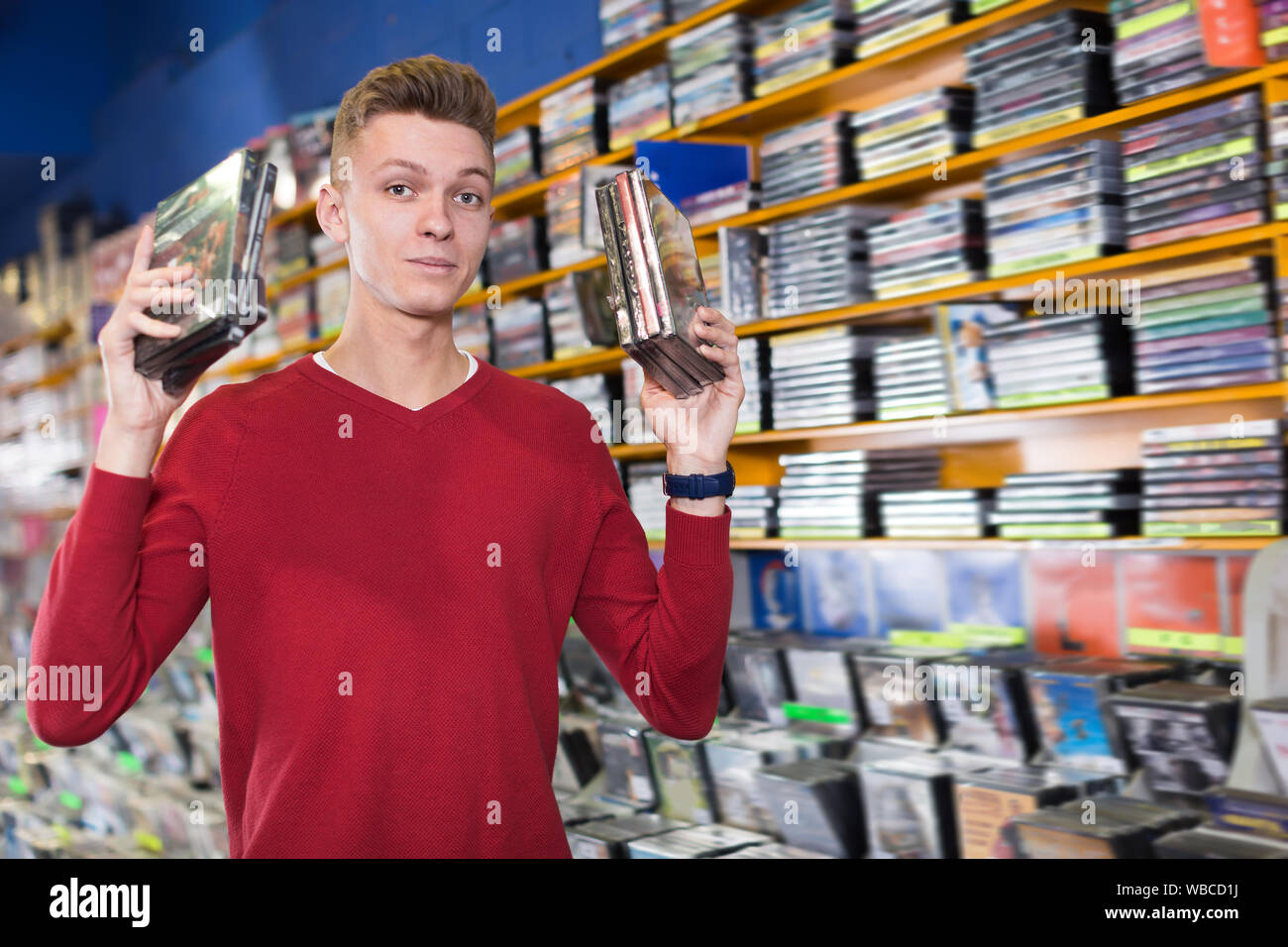 Modern man choosing movies on DVD from large assortment at store Stock ...