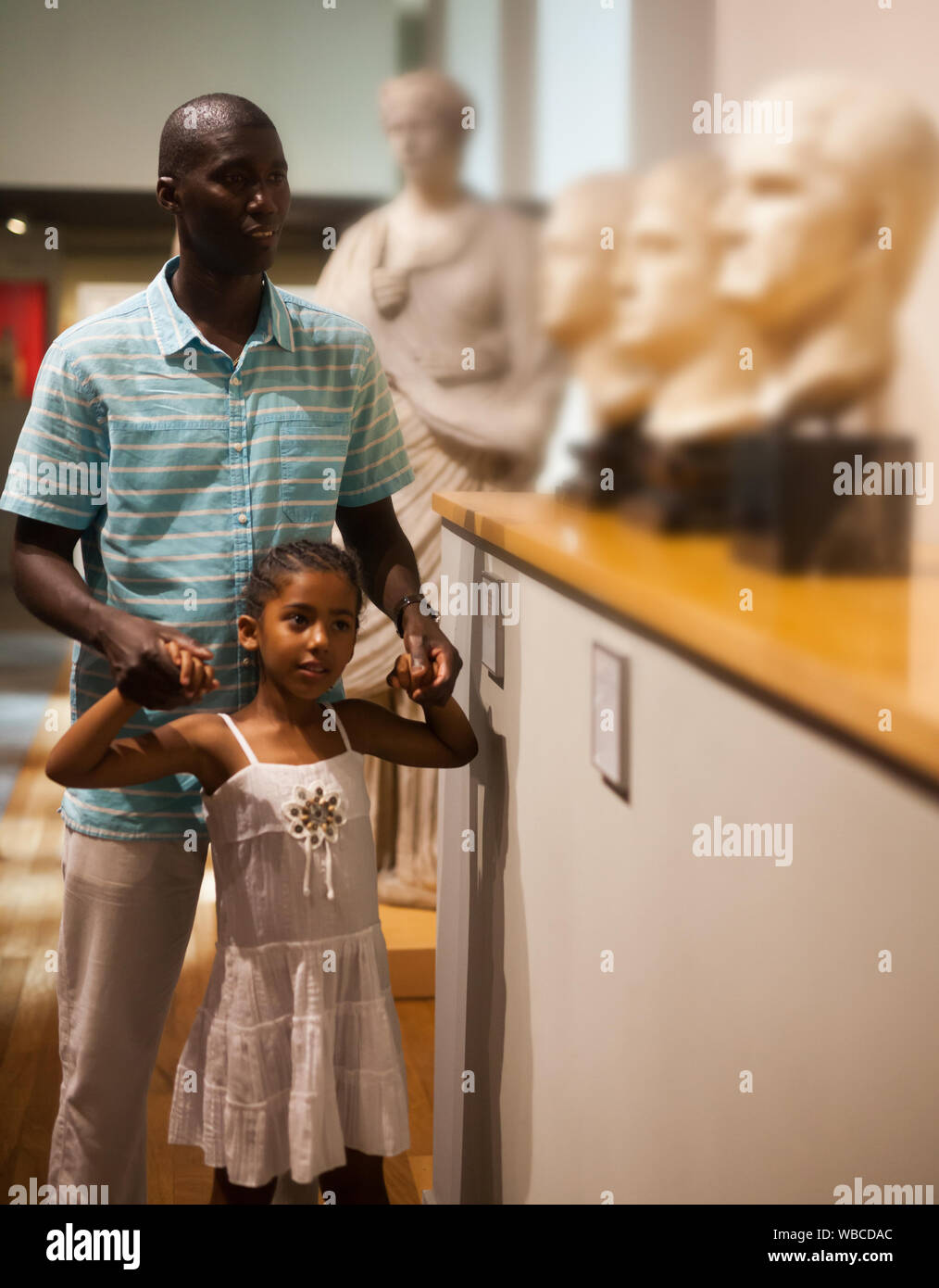 African American man and his little daughter looking at exhibits of ...