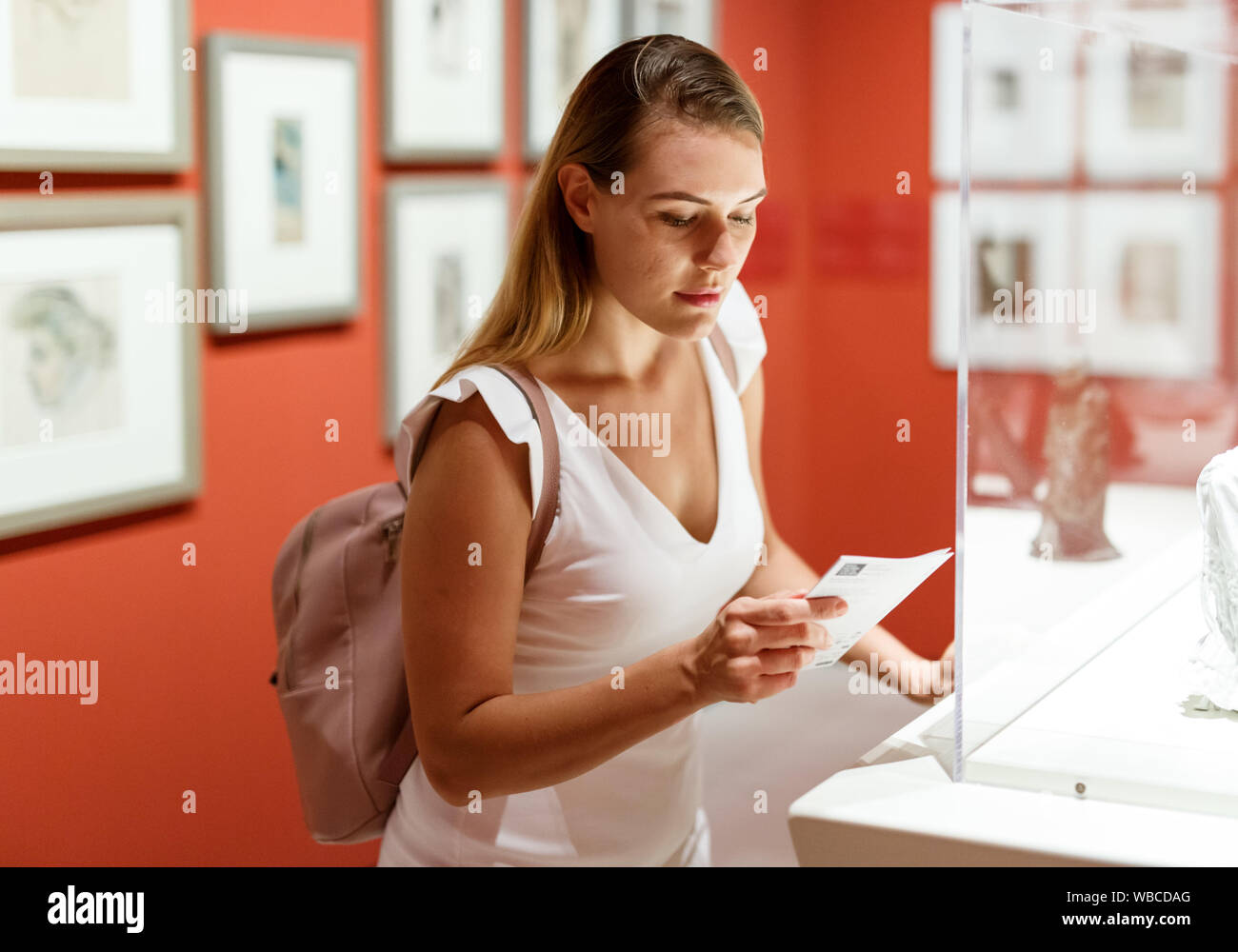 Positive woman observing with interest exhibition under glass in art ...