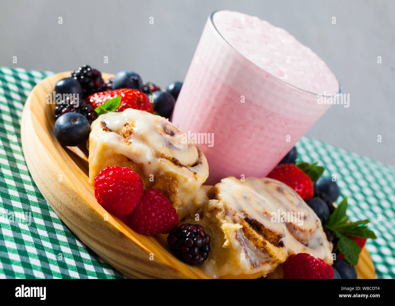 Healthy vitamin milkshake with rolled cinnamon buns served on wooden ...