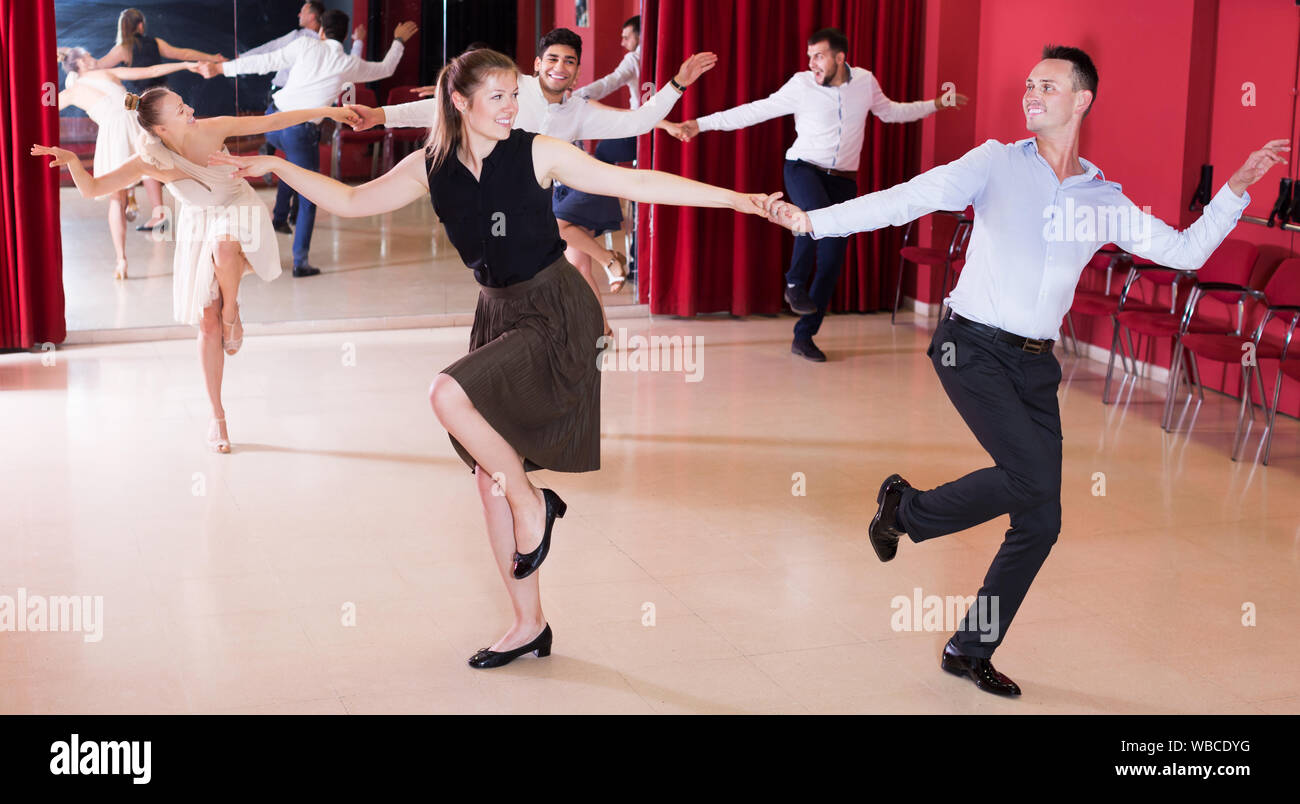 Active adult dancing couples enjoying latin dances in modern studio ...