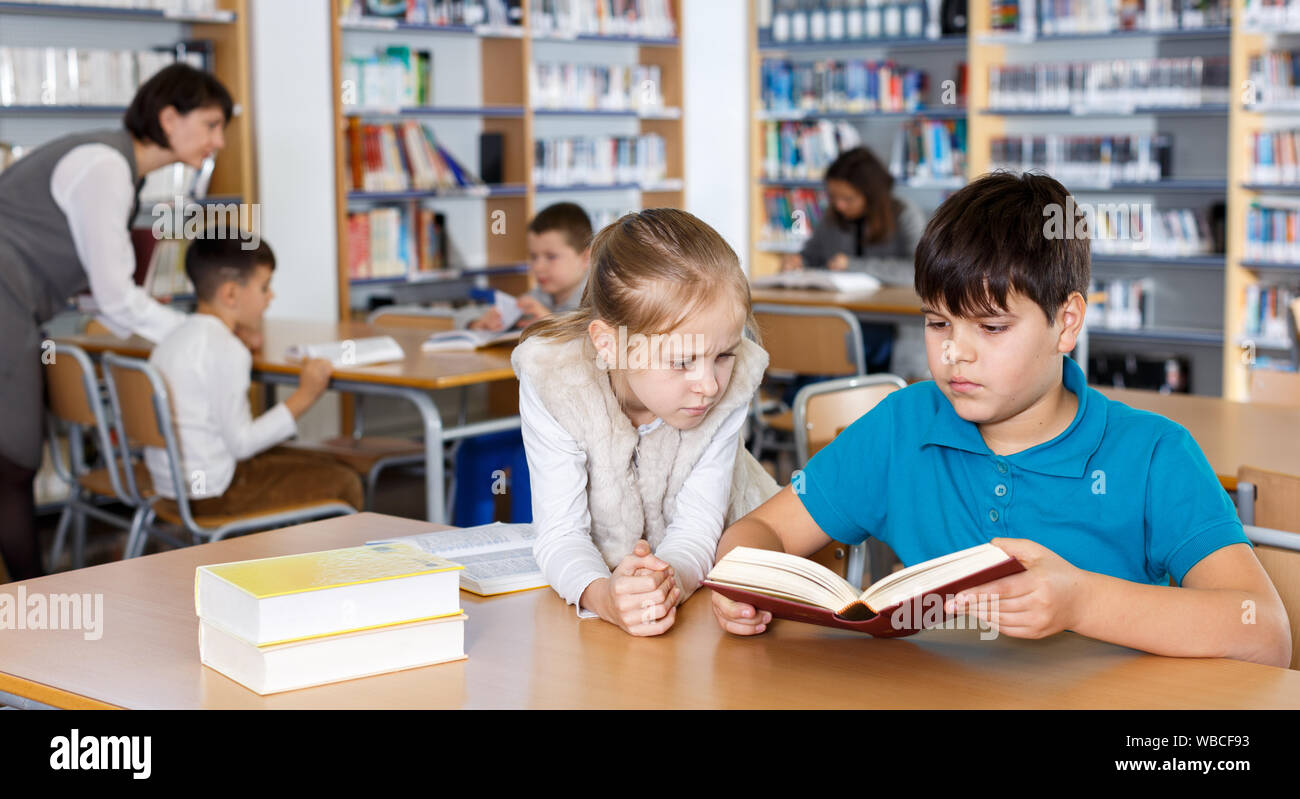 School friends spending time together in library, reading books Stock ...