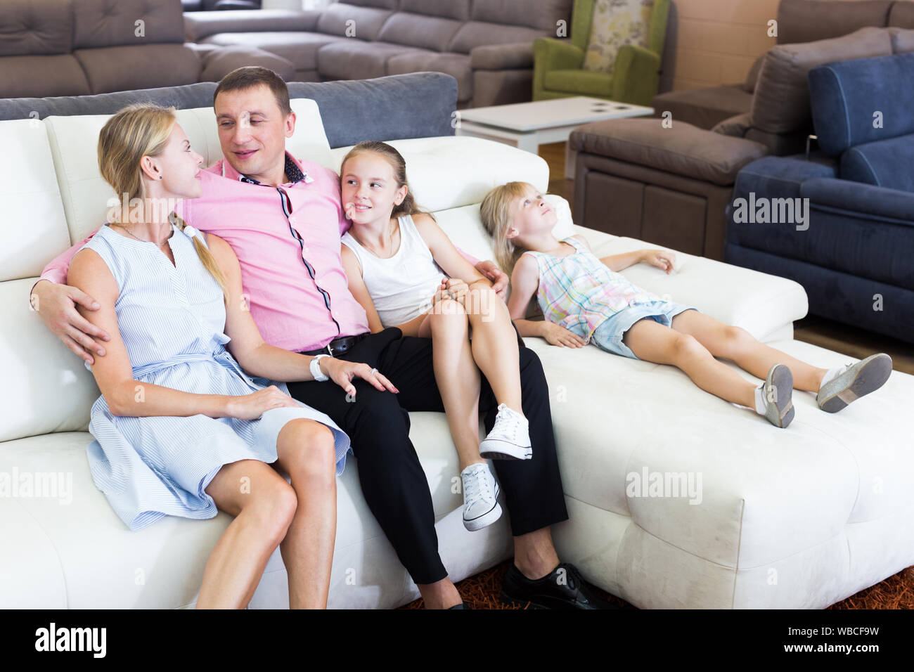 Parents with kids is pleased by new sofa in furniture store Stock Photo ...