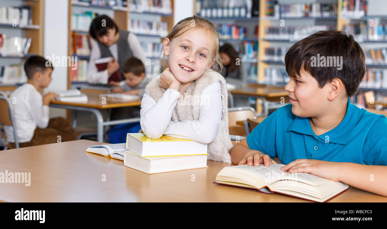 Cute tween girl and intelligent boy studying together in school library ...