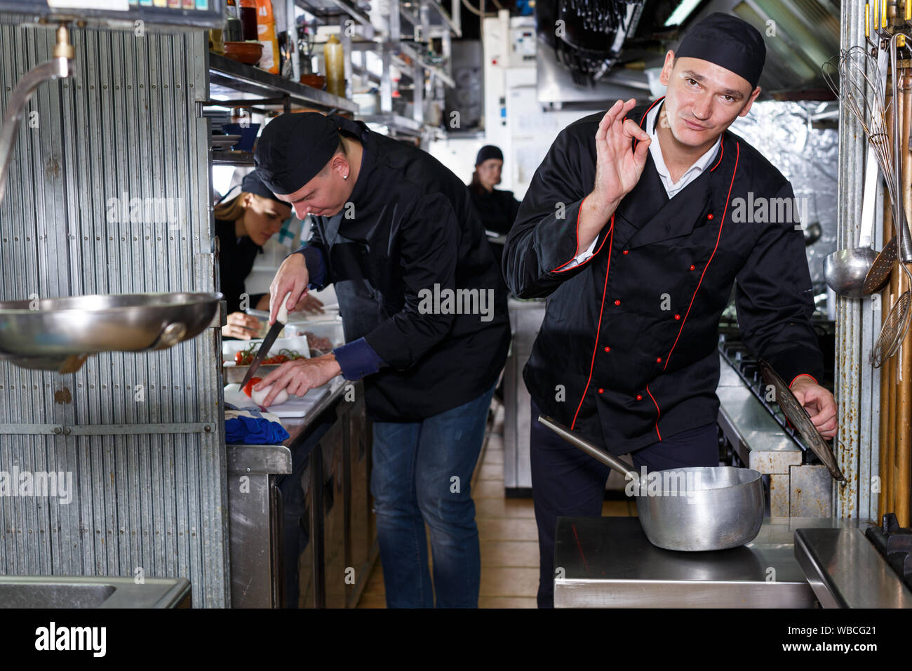 Cheerful cooks dressed in black uniform at restaurant kitchen Stock ...