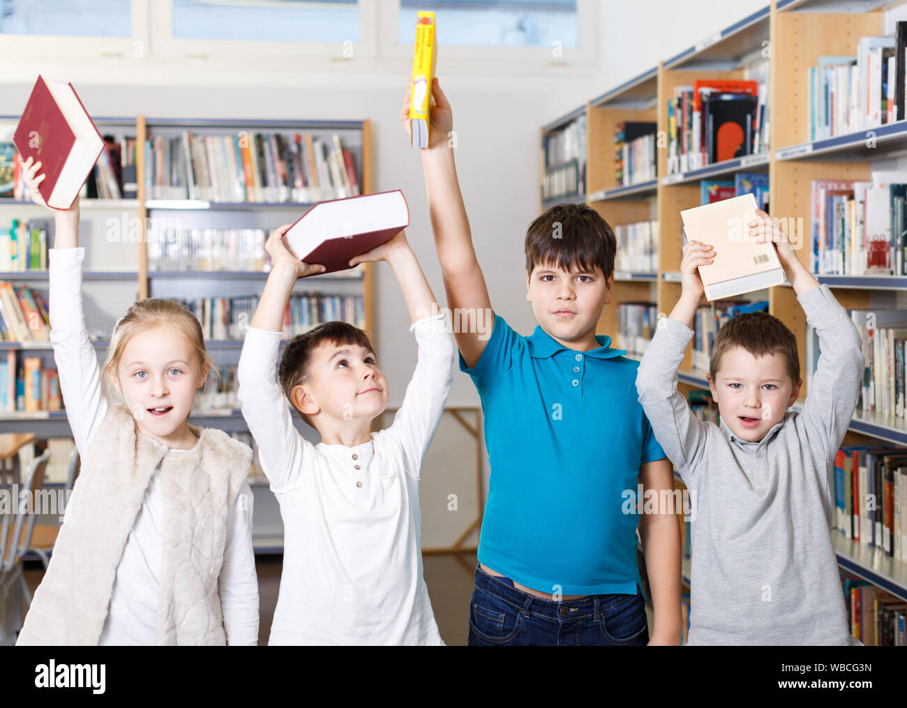 Group portrait of happy children standing with books in hands in modern ...