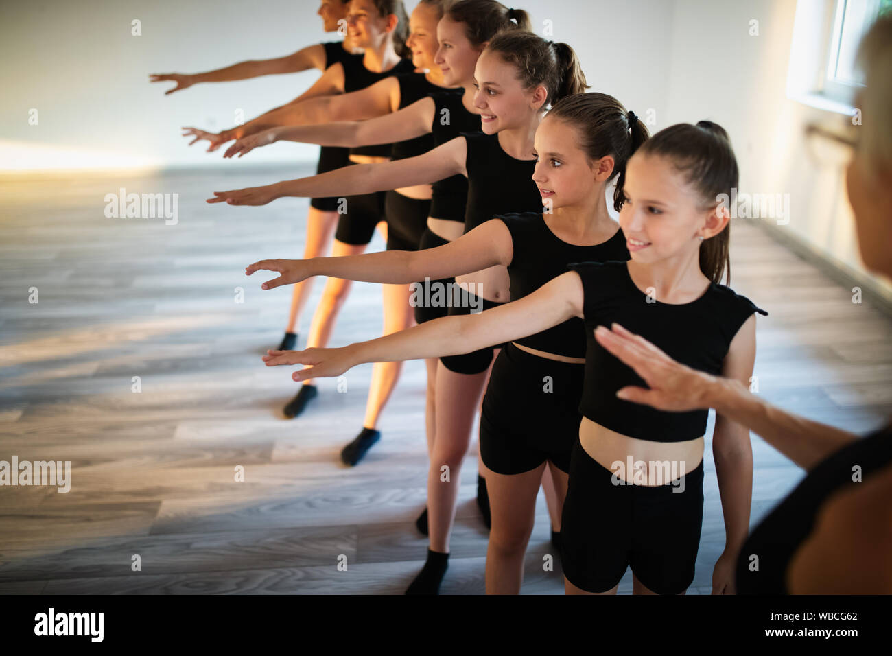 Group of fit happy children exercising ballet and dancing in studio ...