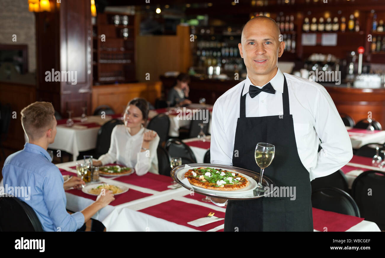Handsome elegant waiter with serving tray welcoming to restaurant Stock ...