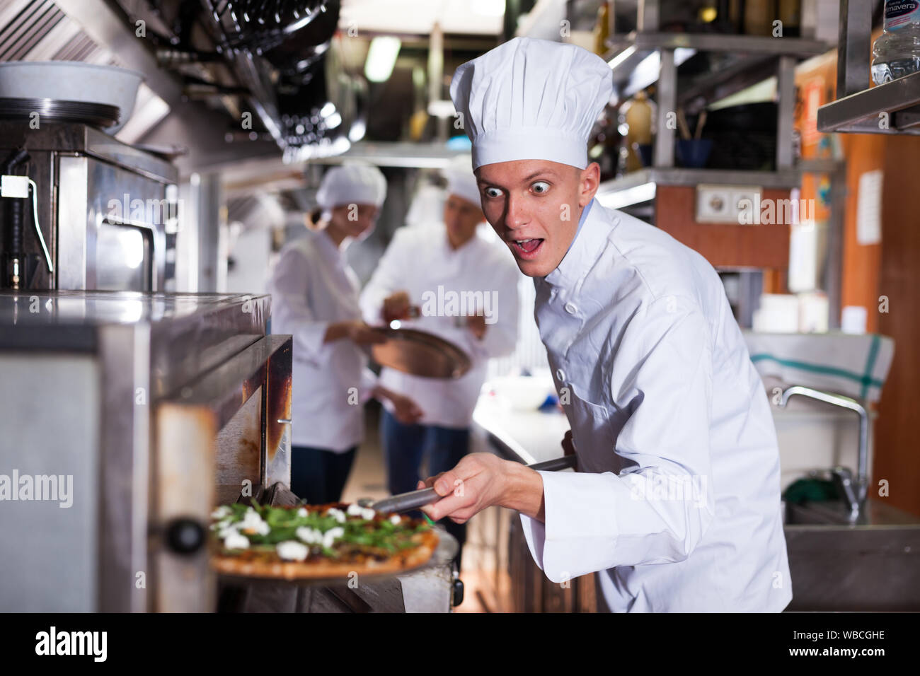 Portrait of happy surprised chef getting ready pizza out of ...