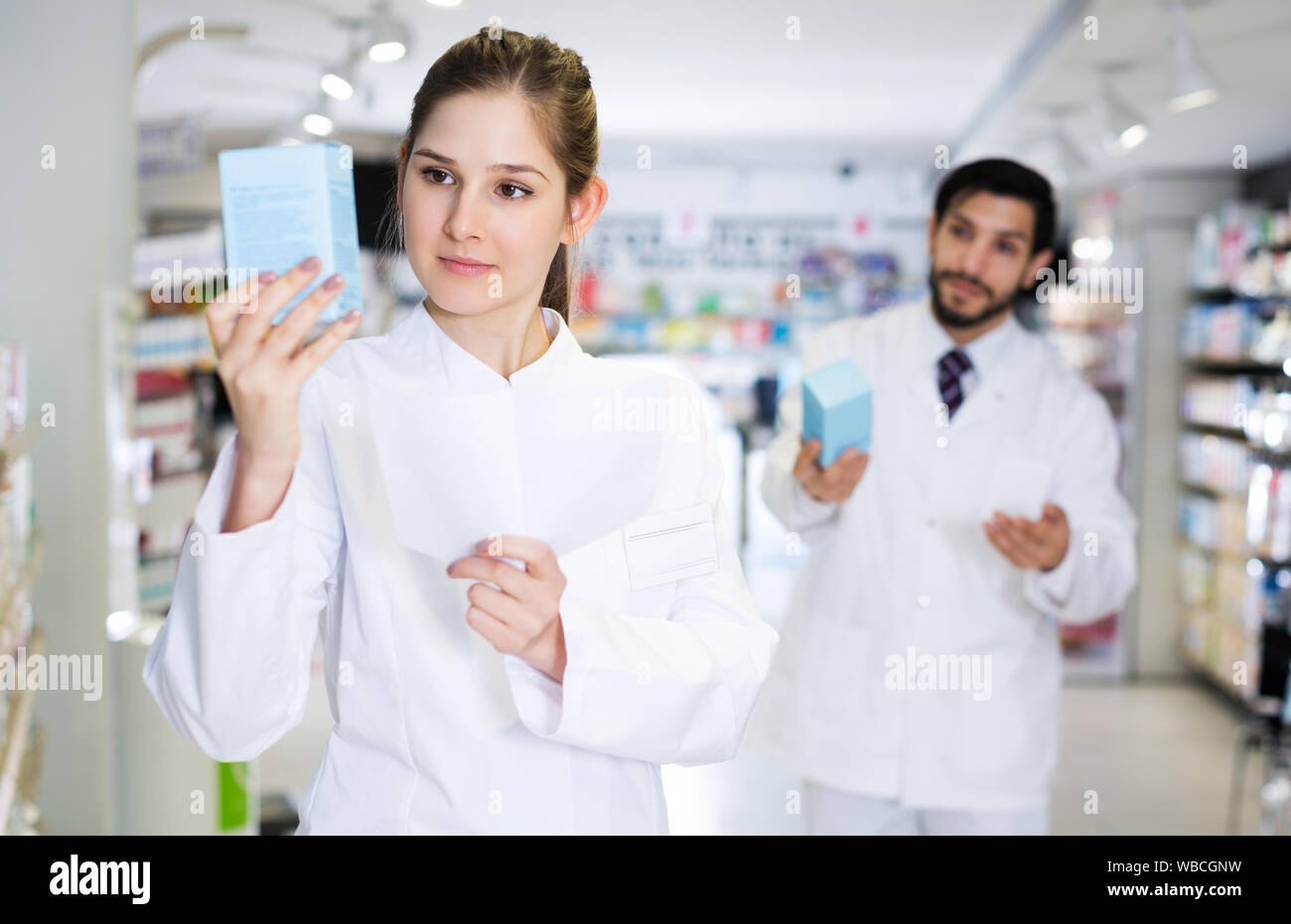 smiling young pharmacist who is standing with medicine on her work ...