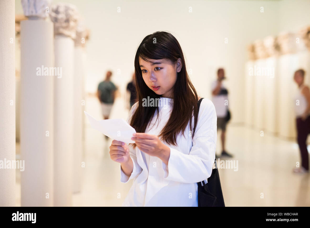 Portrait of young chinese woman with guide looking at exhibition in ...
