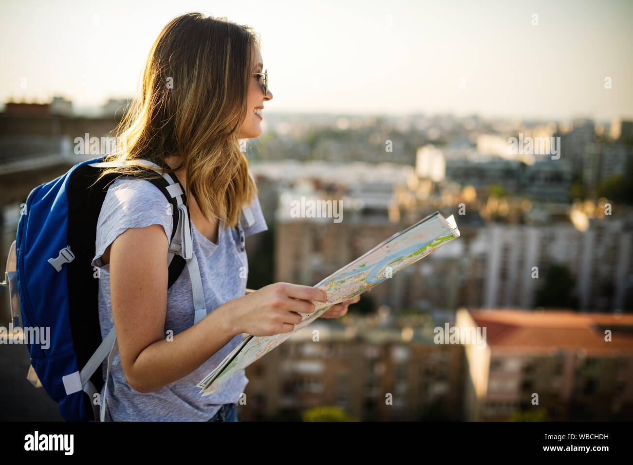 Happy female tourist searching road to hotel on map in city during ...
