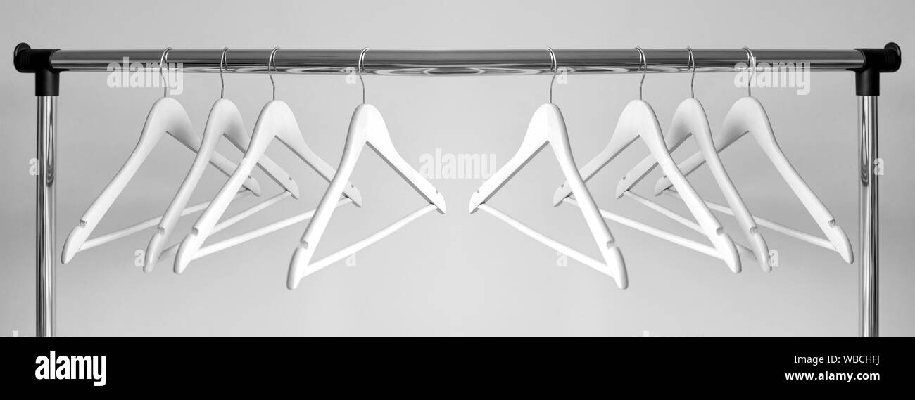 Empty clothes hangers on metal rail against grey background ...
