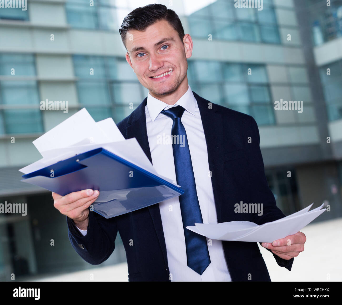 Smiling director is examining documents before signing outdoors Stock ...