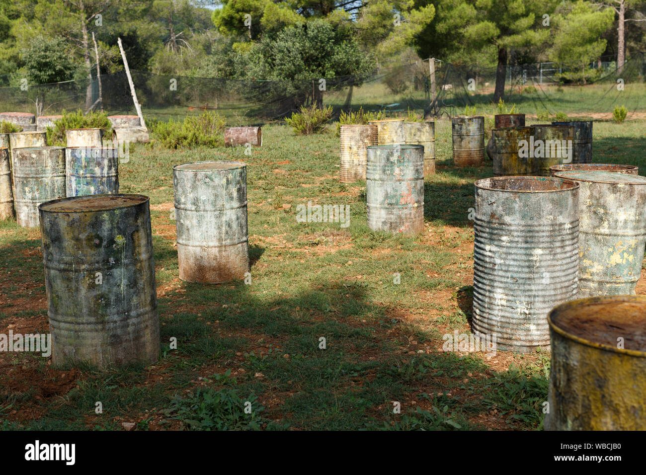 Old rusty fuel barrels with traces of marker guns on open paintball ...