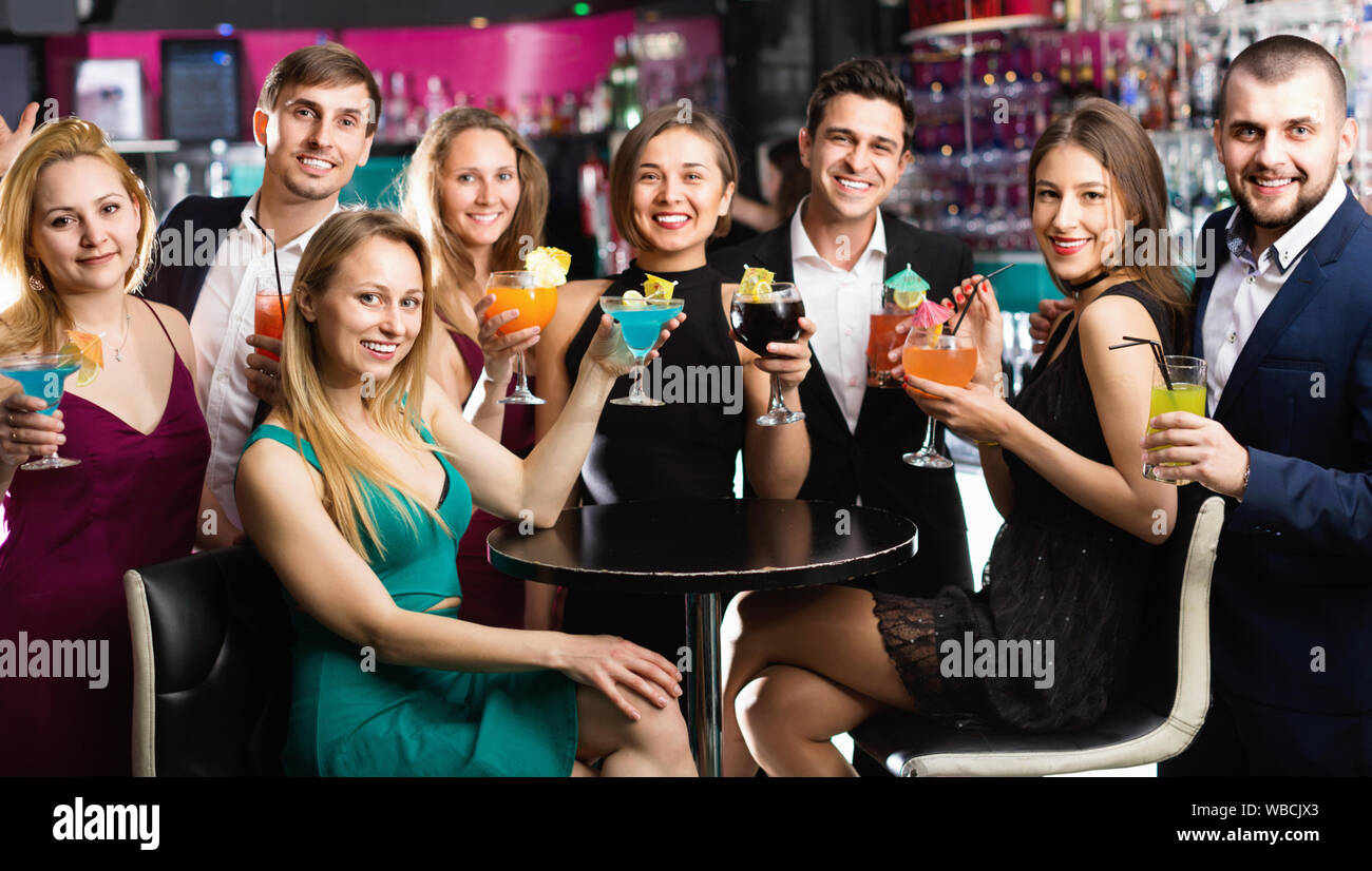 Positive colleagues dancing on corporate party with cocktails in hands ...