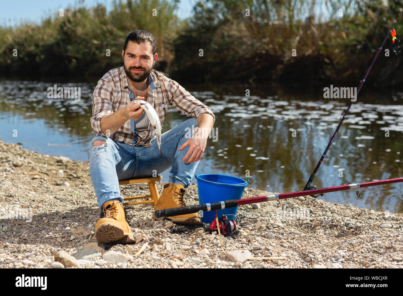 Adult male fisherman holding fish in his hands Stock Photo - Alamy