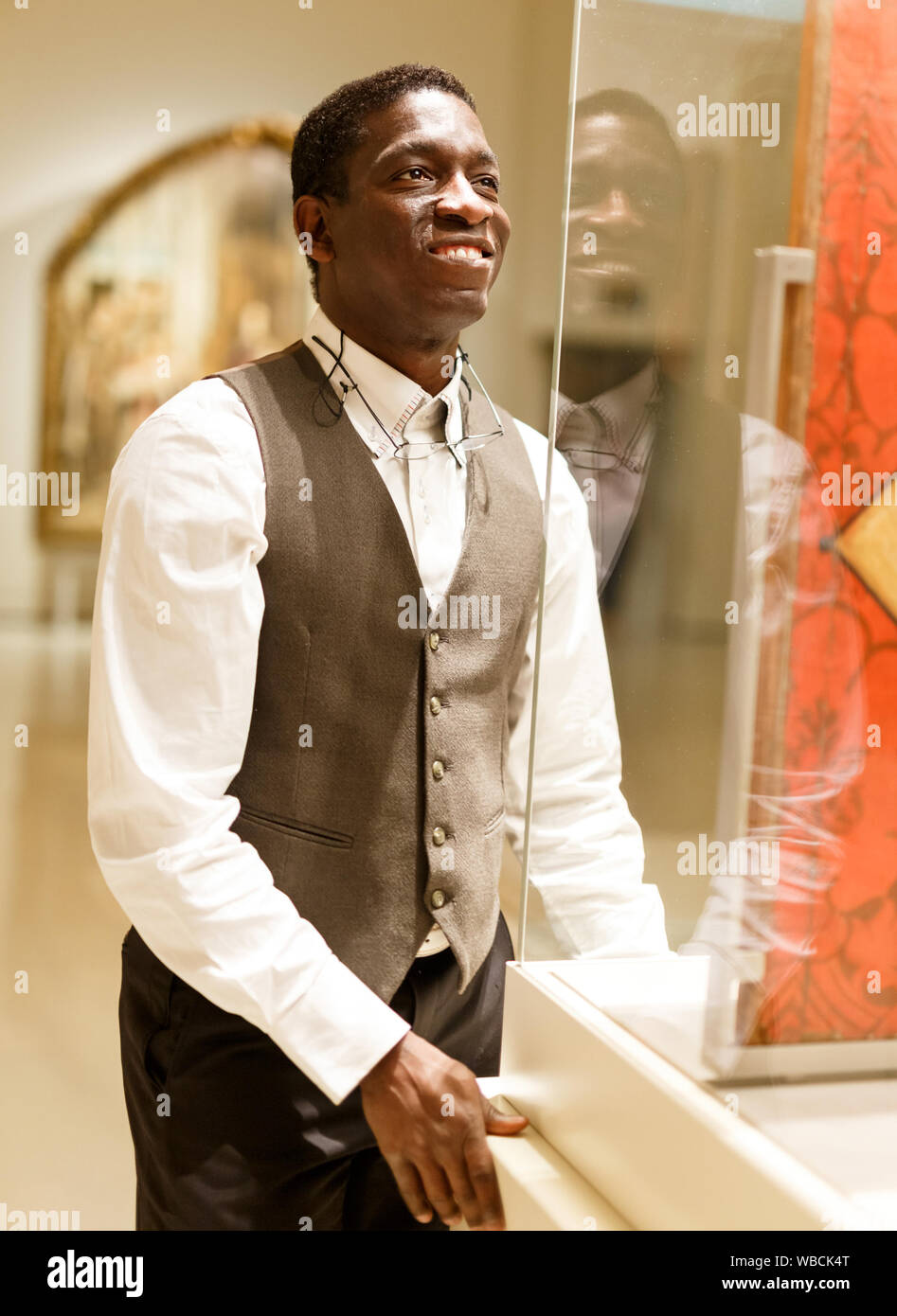 African man standing at hall of Art Museum among exhibits of antiquity ...