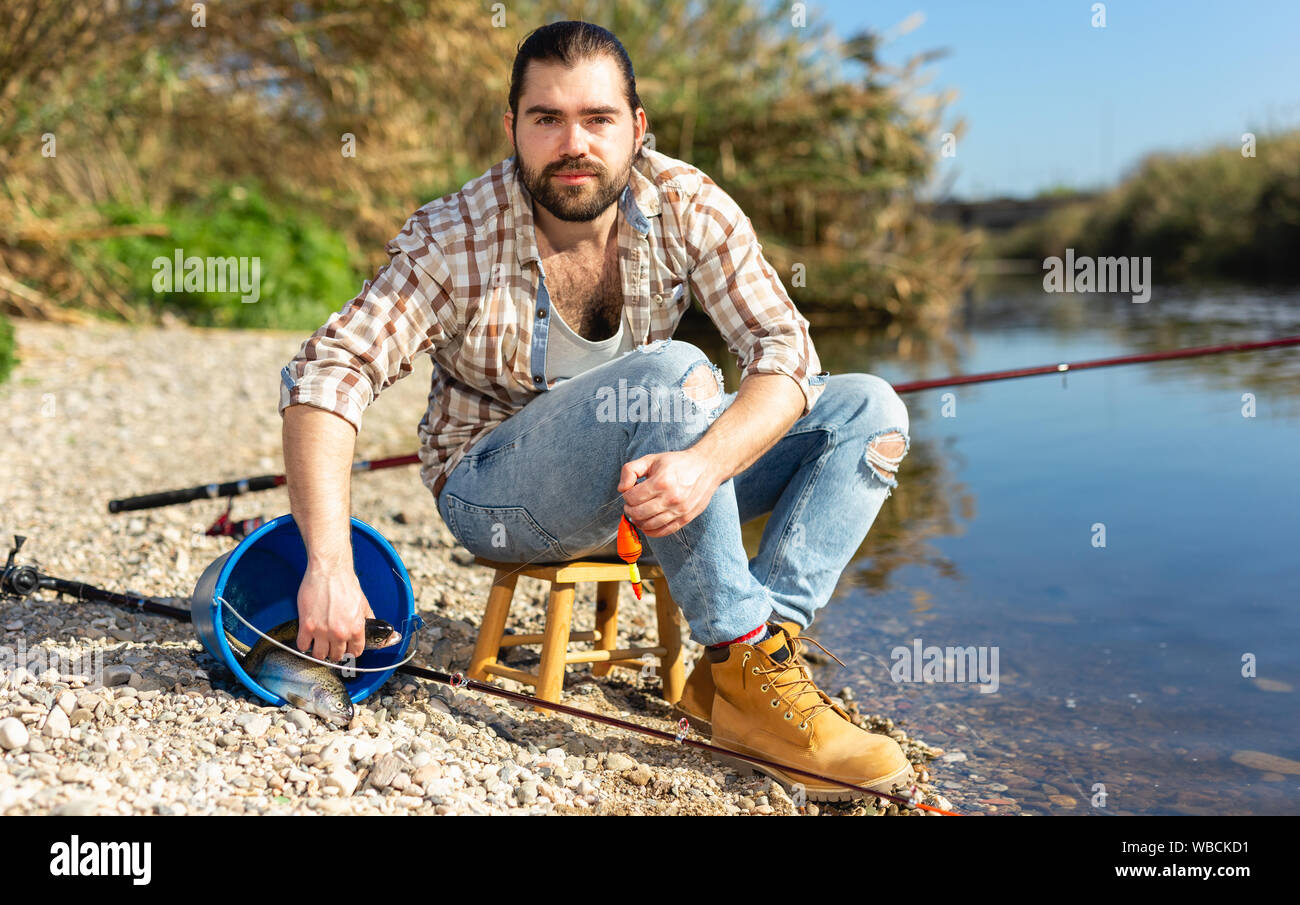 Bearded adult man posing with fish near river in summertime Stock Photo ...