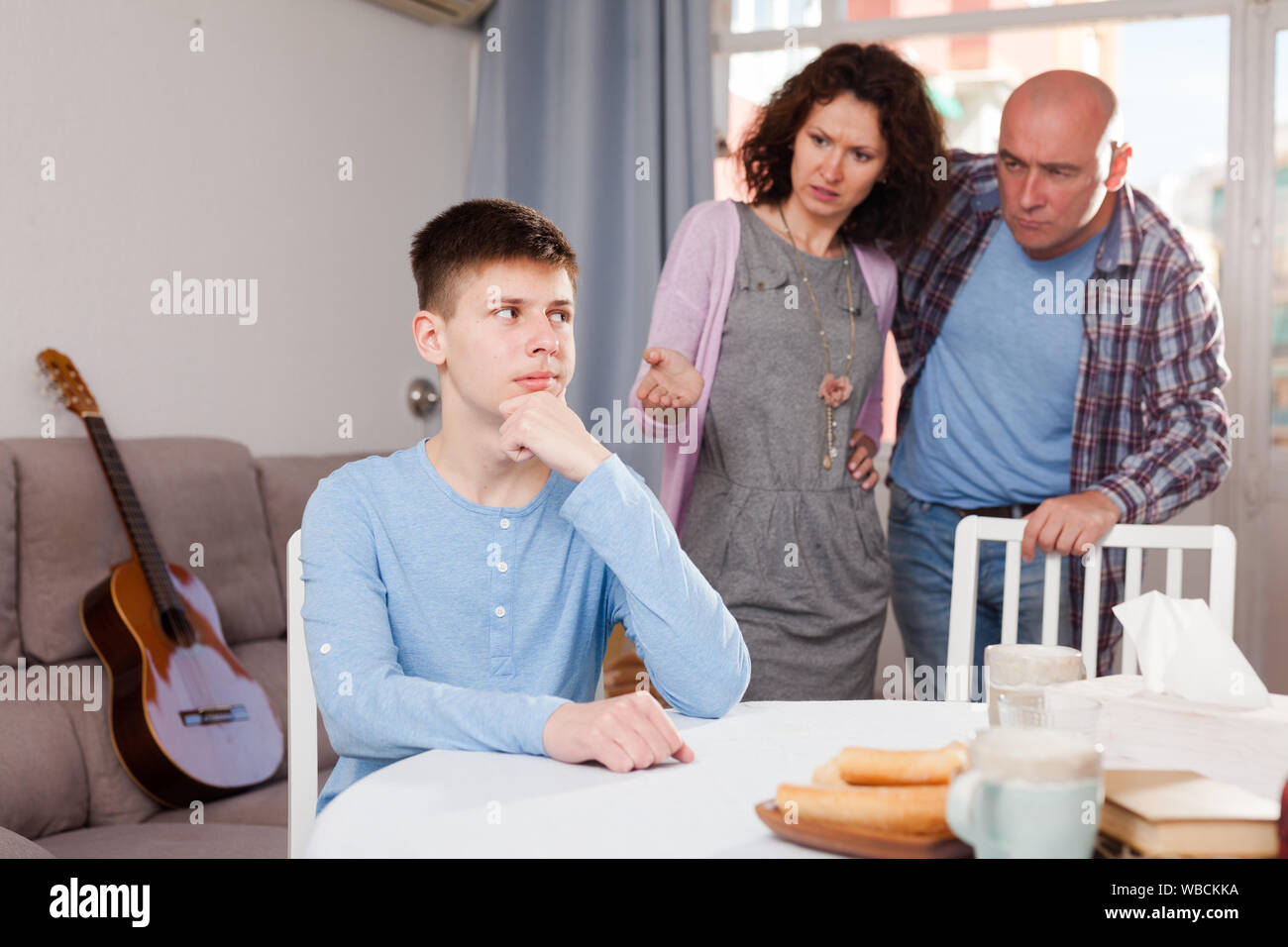 Offended teenager sitting at home, listening to reprimanding from his ...