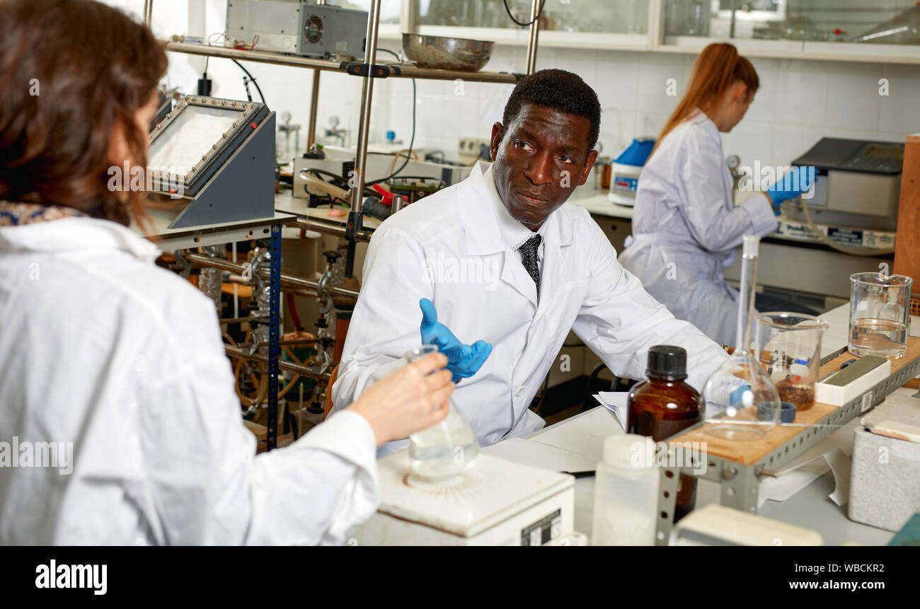 Focused lab technicians man writing report of chemical experiments ...