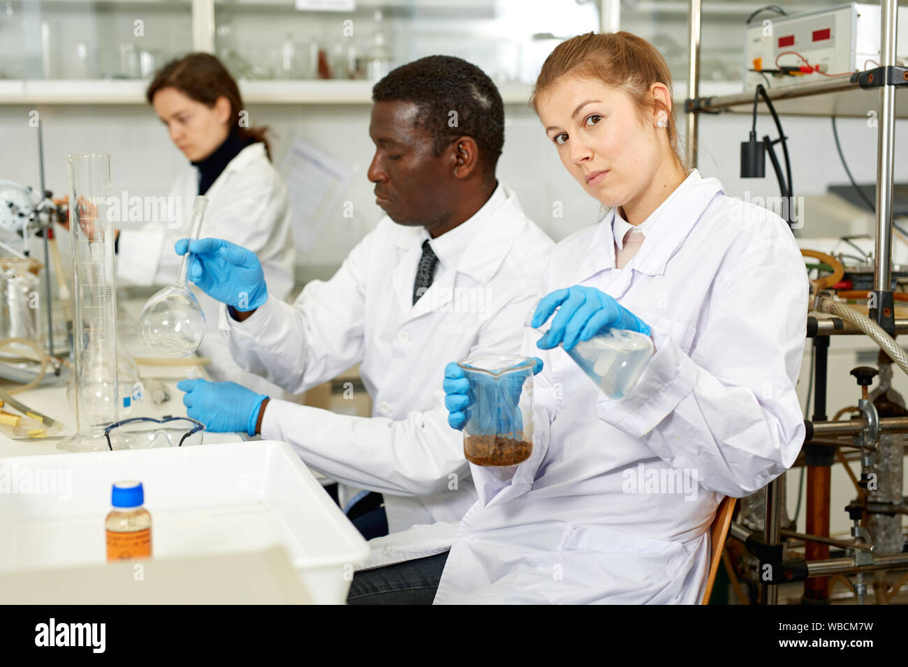 Focused women lab technicians in glasses working with reagents and test ...