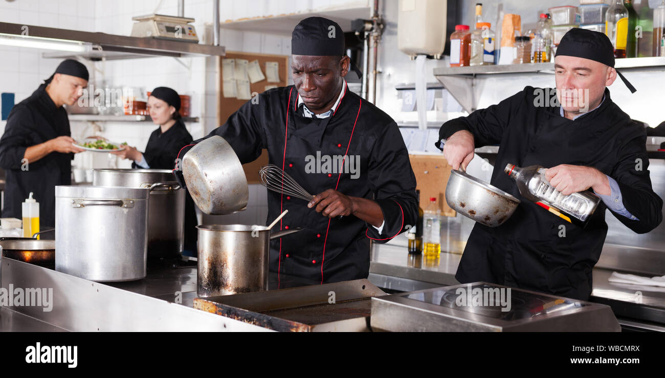 Positive cooks in process of working in kitchen of restaurant Stock ...