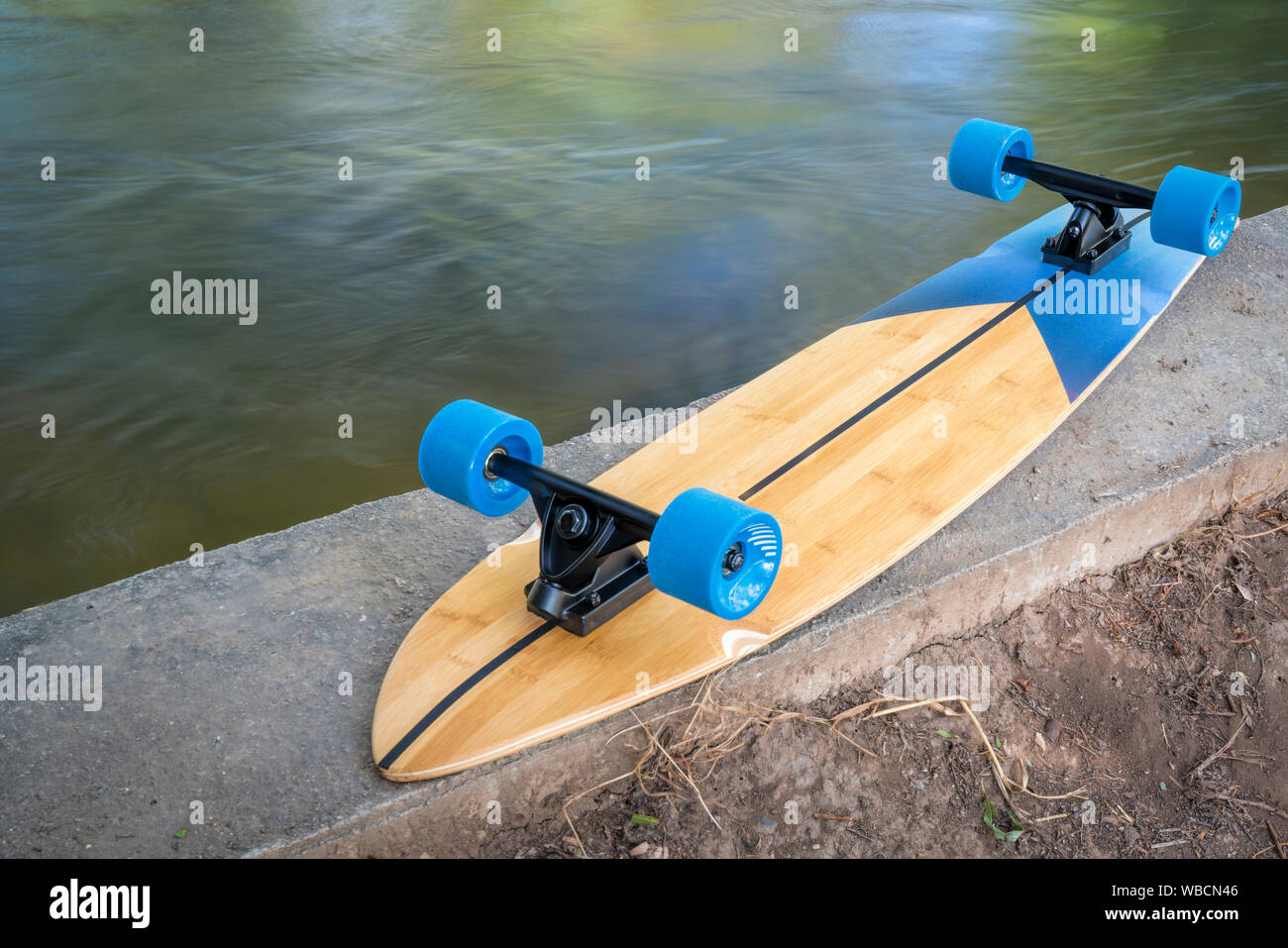 cruising longboard with blue wheels on a river shore Stock Photo - Alamy