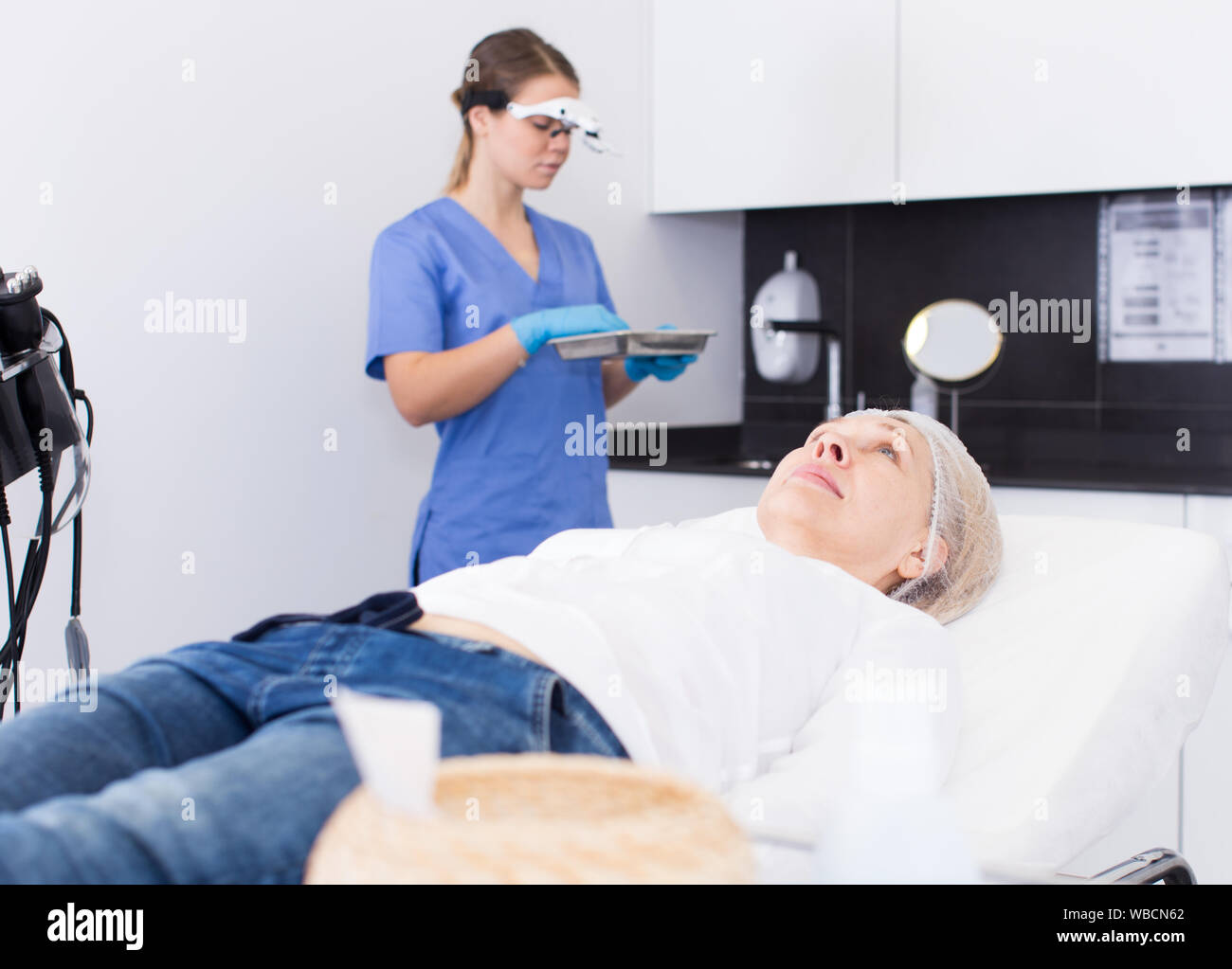 Mature female client lying on sofa waiting for cosmetological treatment ...