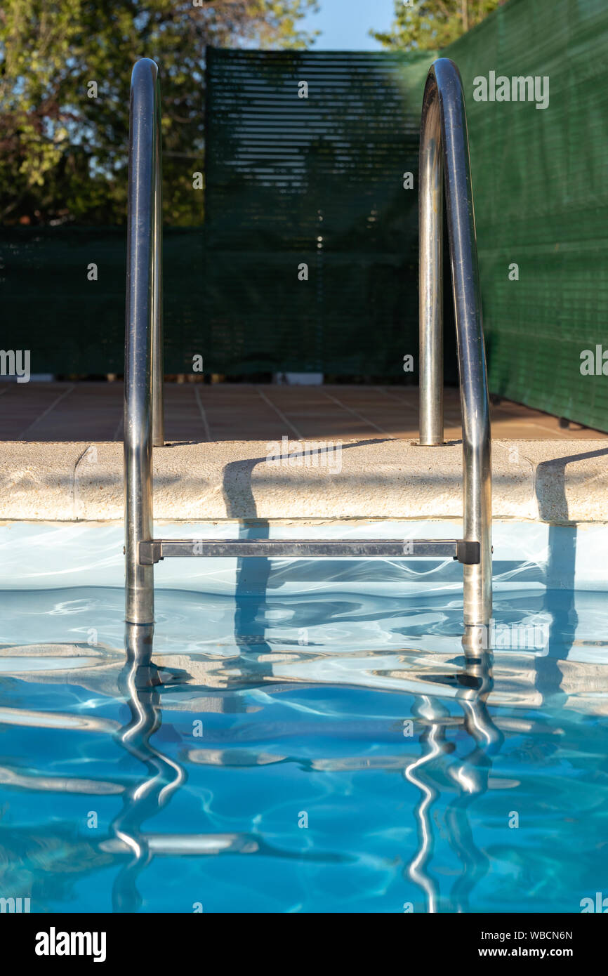 Swimming pool ladder and water surface in front Stock Photo - Alamy