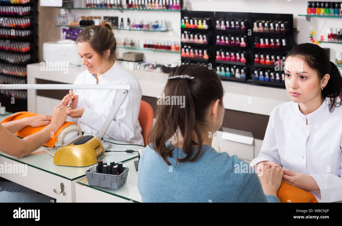 nail technicians performing manicure procedure behind the workplace in ...