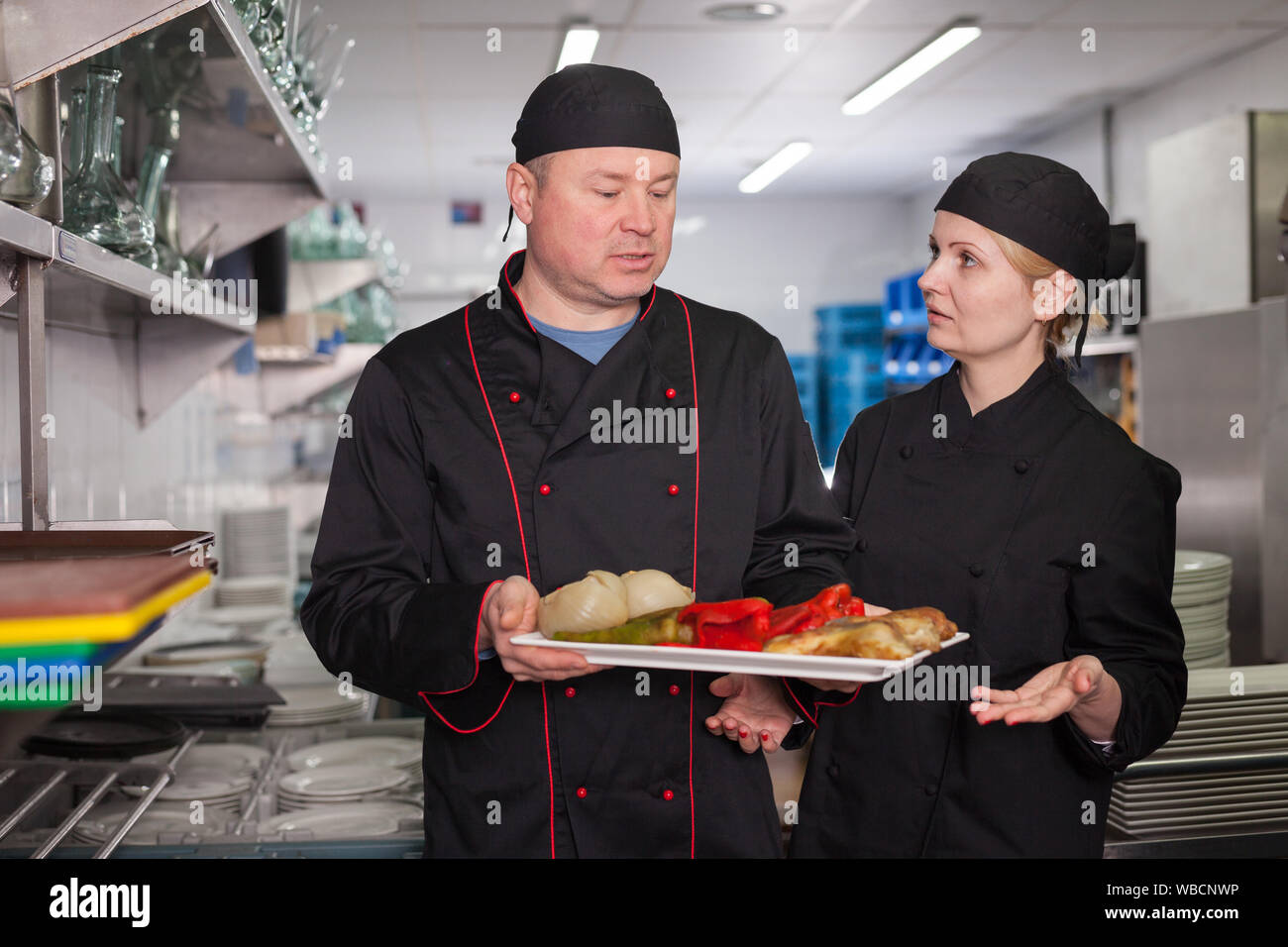 Man and woman professional cooks holding finished dish, ready to serve ...