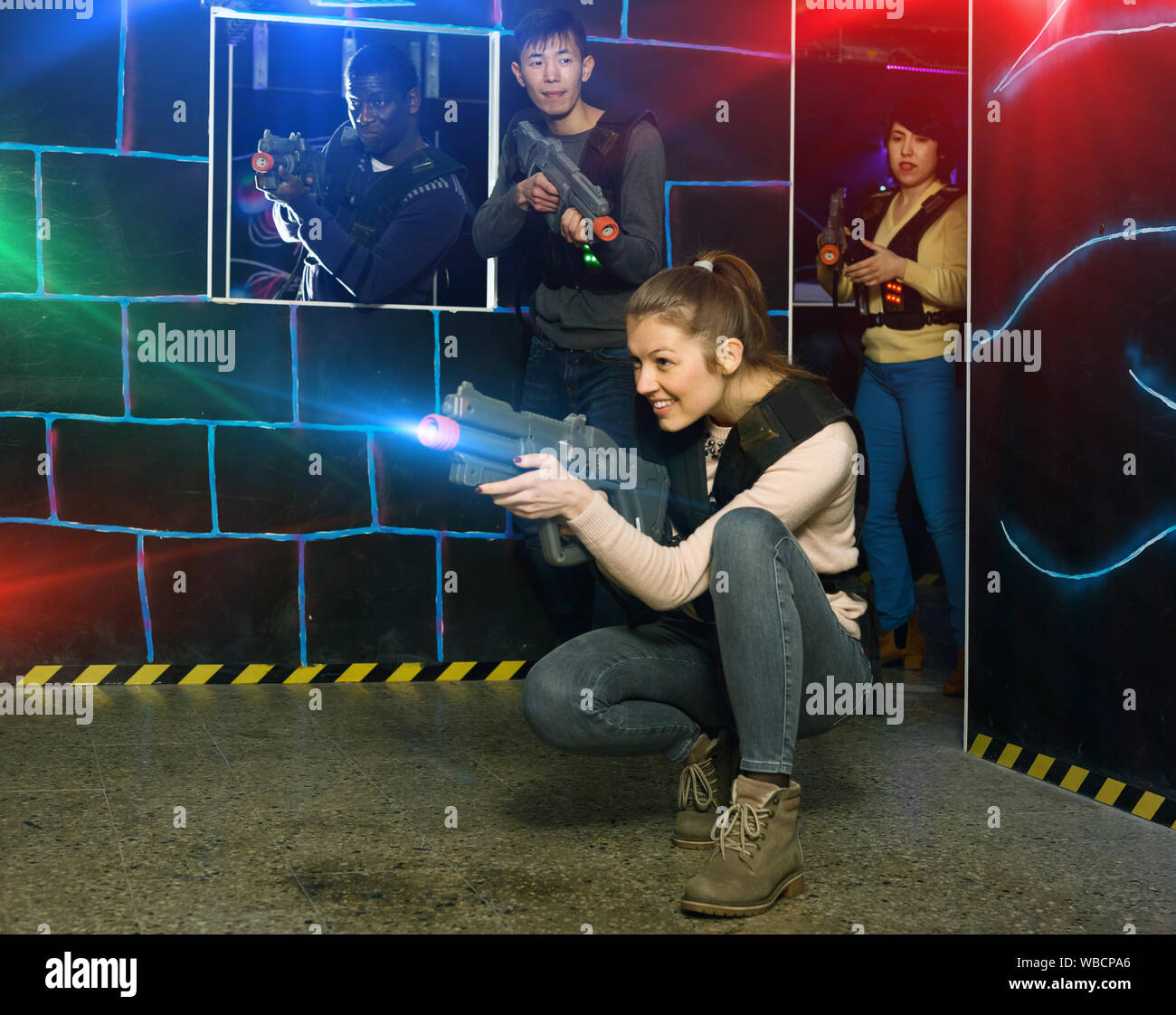 Emotional young girl with laser pistol playing laser tag with ...