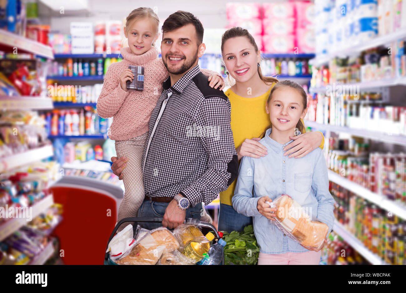 parents with two little girls with purchases during family shopping in ...