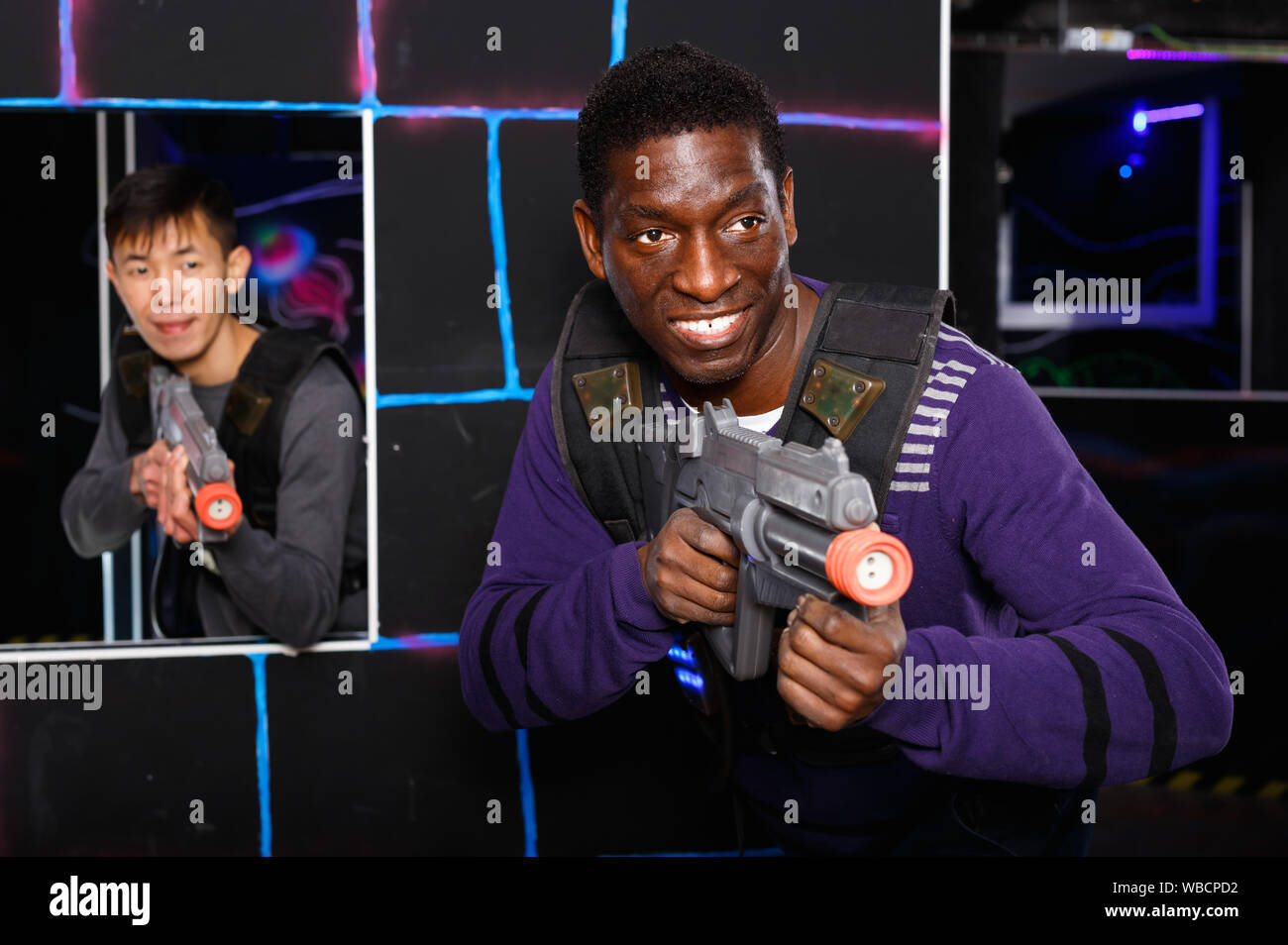 Portrait of cheerful friendly African-American with laser gun having ...