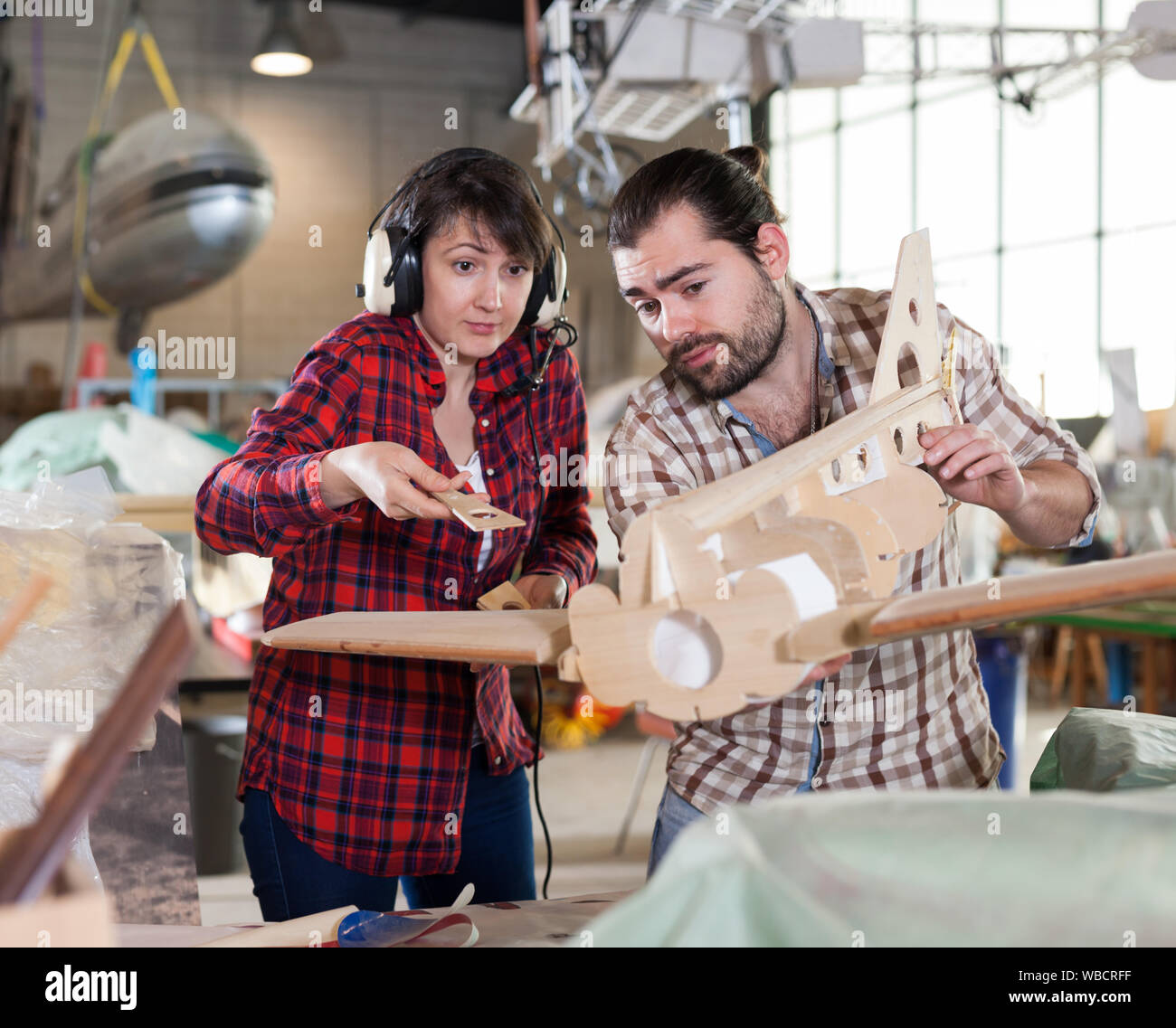 Female and male hobbyists engaged in creating plane models in aircraft ...