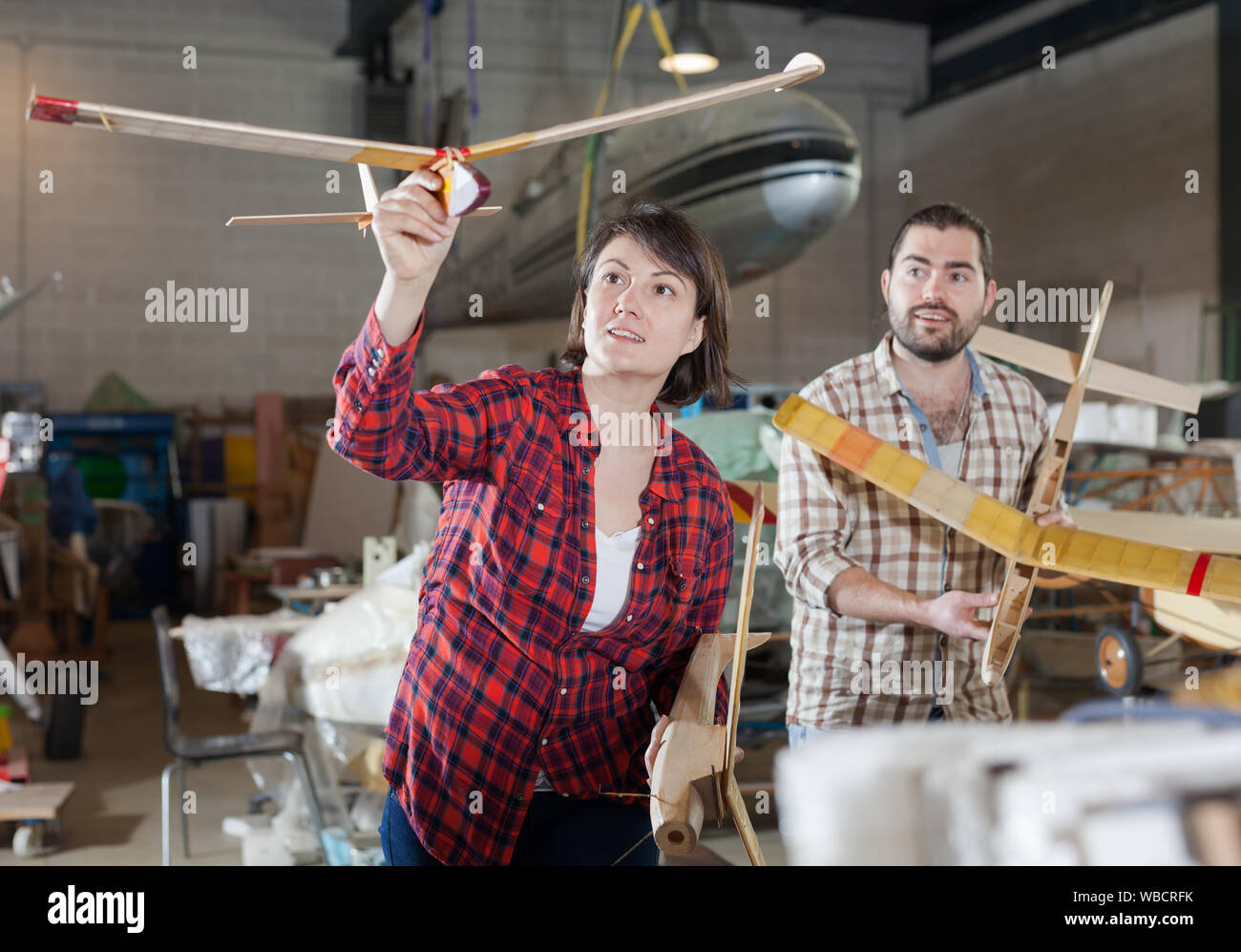 Portrait of positive couple having fun with light plane models in ...