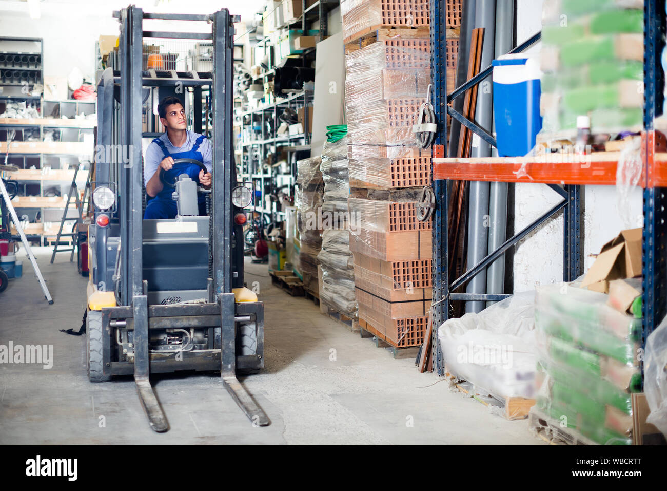Seller is driving loader between the rows in the building store Stock ...