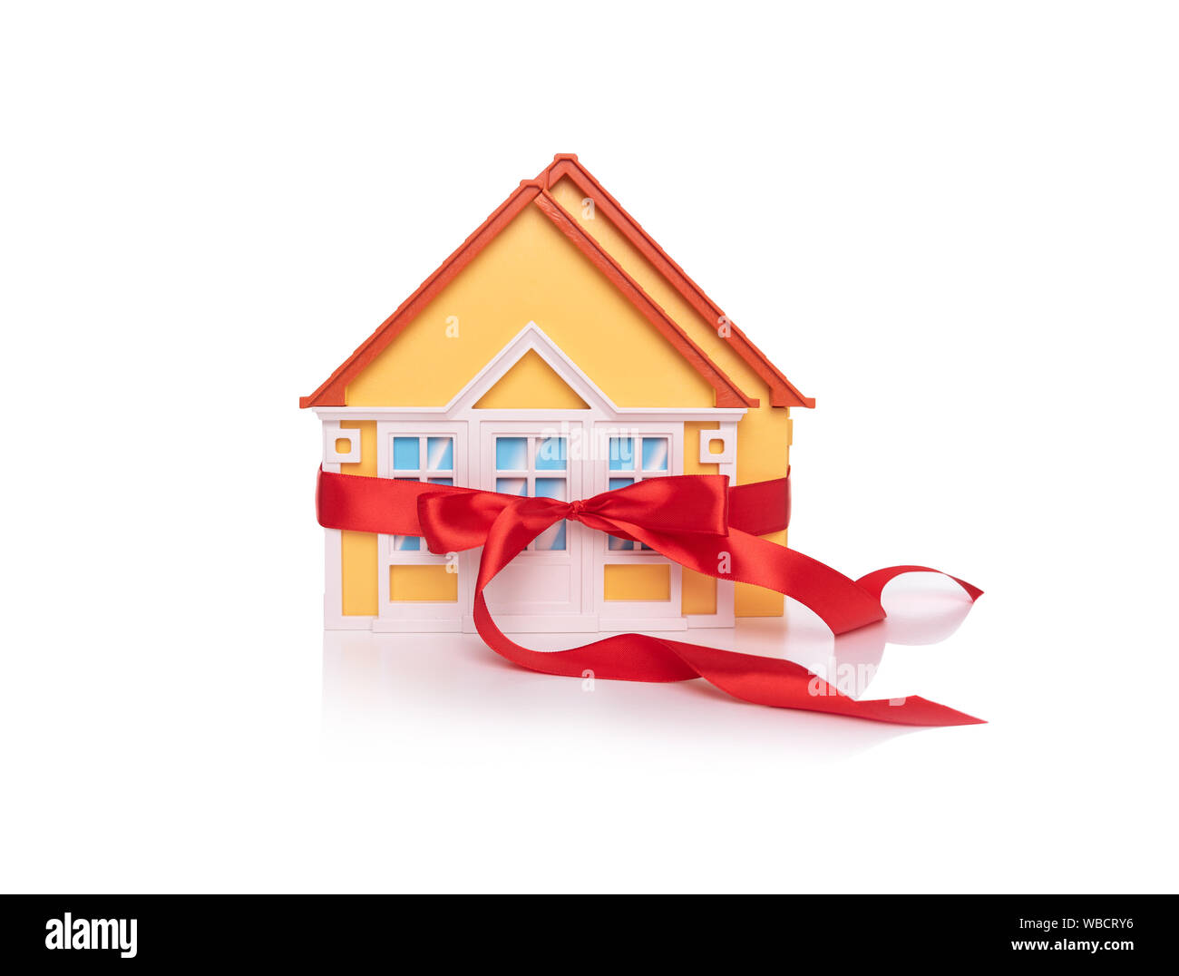 Toy house model bandaged with a red ribbon on white background Stock ...